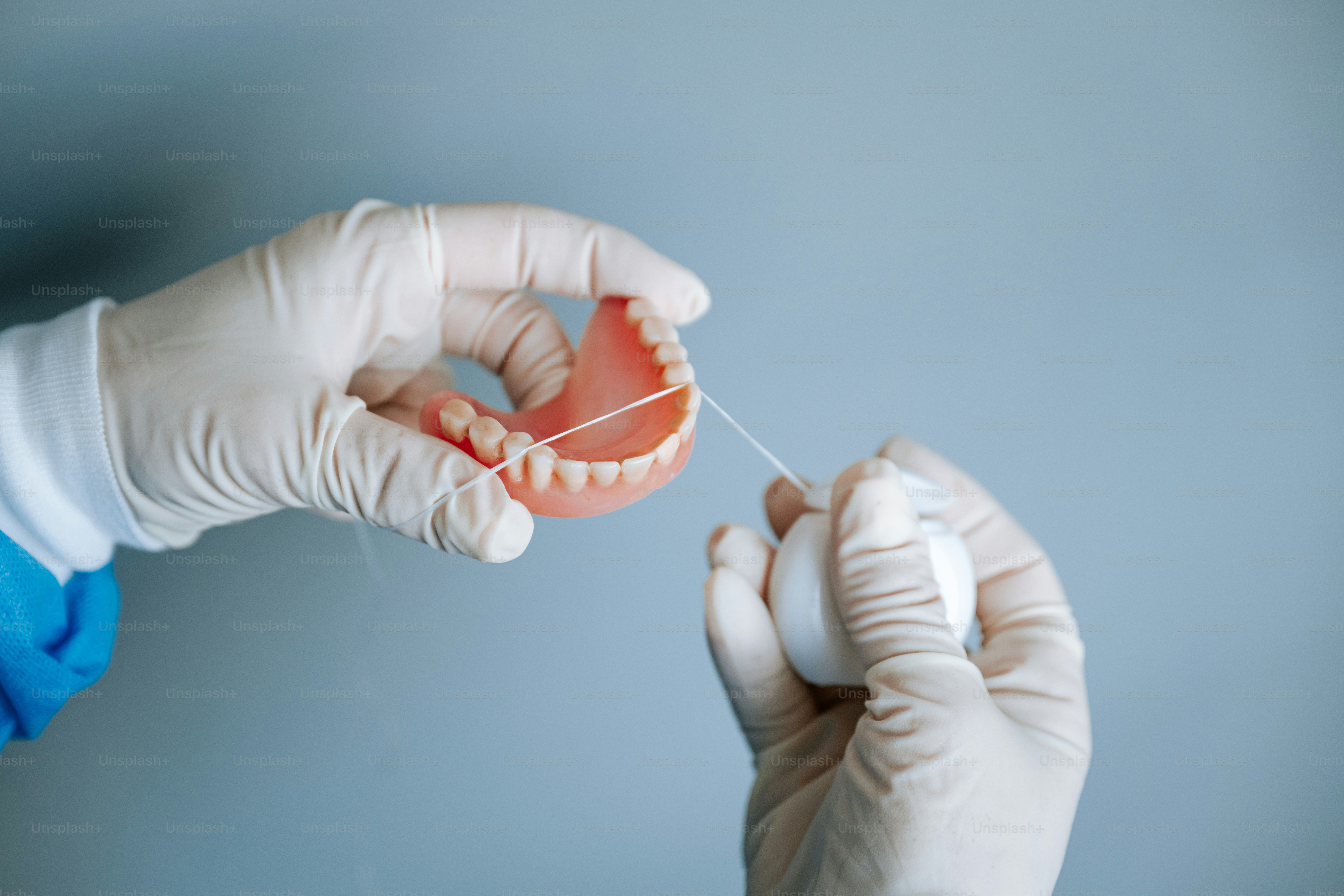 A person flossing a set of dentures. photo – Dental Image on Unsplash