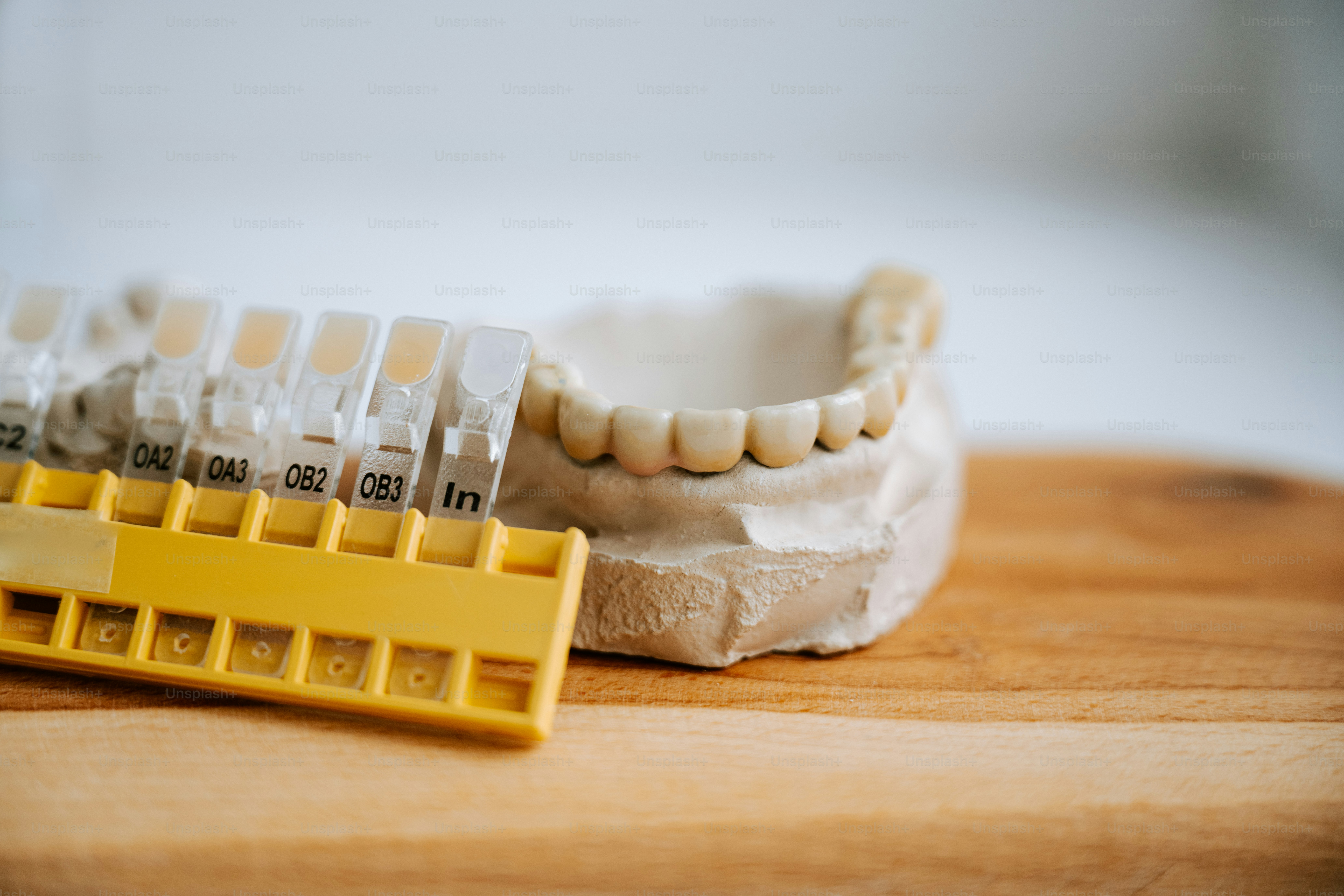 Dental teeth models and color guides sit on wood. photo – Dental Image ...