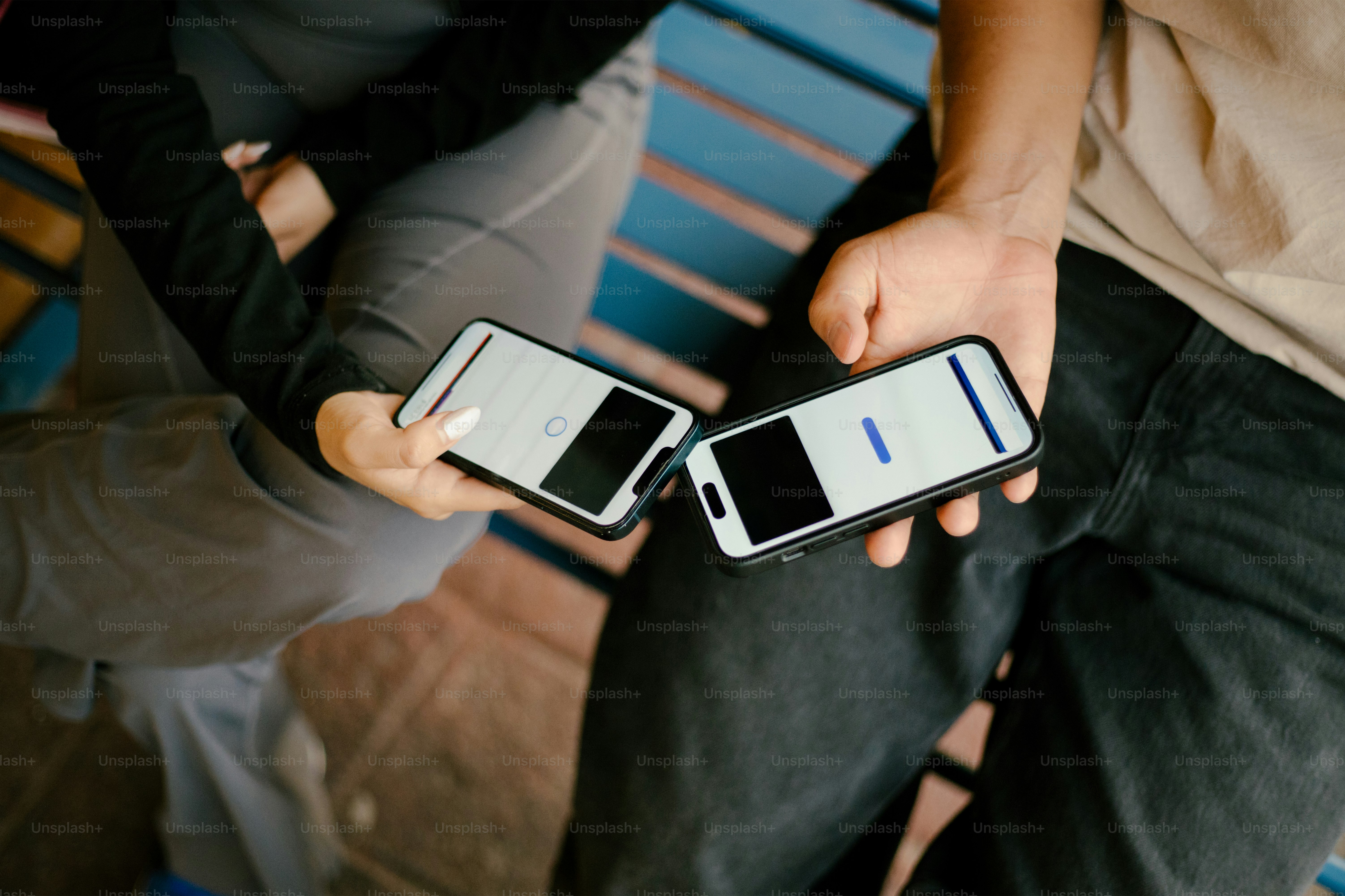 Two people are holding and looking at phones. photo – Image on Unsplash