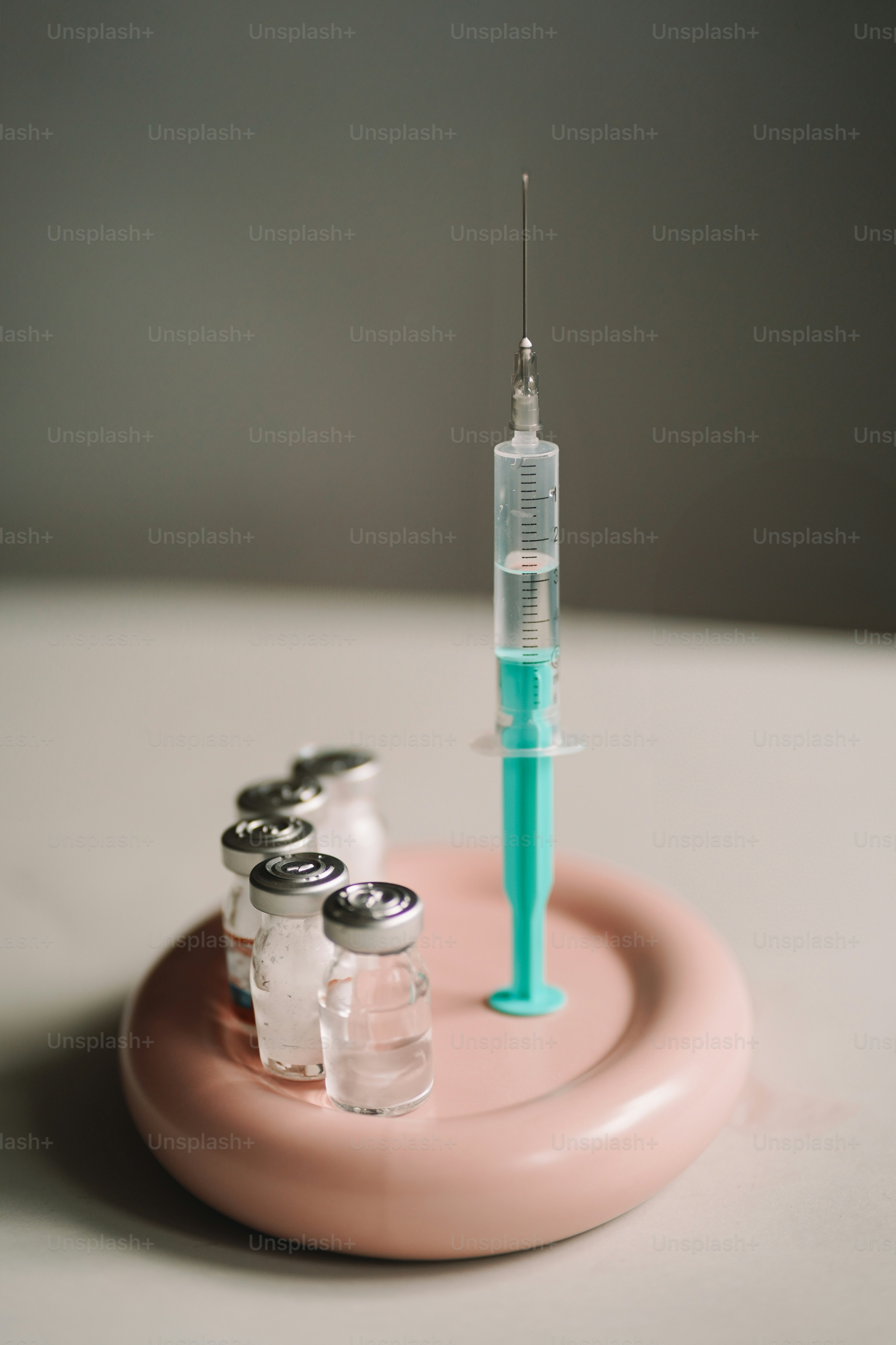 Vaccine vials and a syringe sit on a plate. photo – Health Image on ...