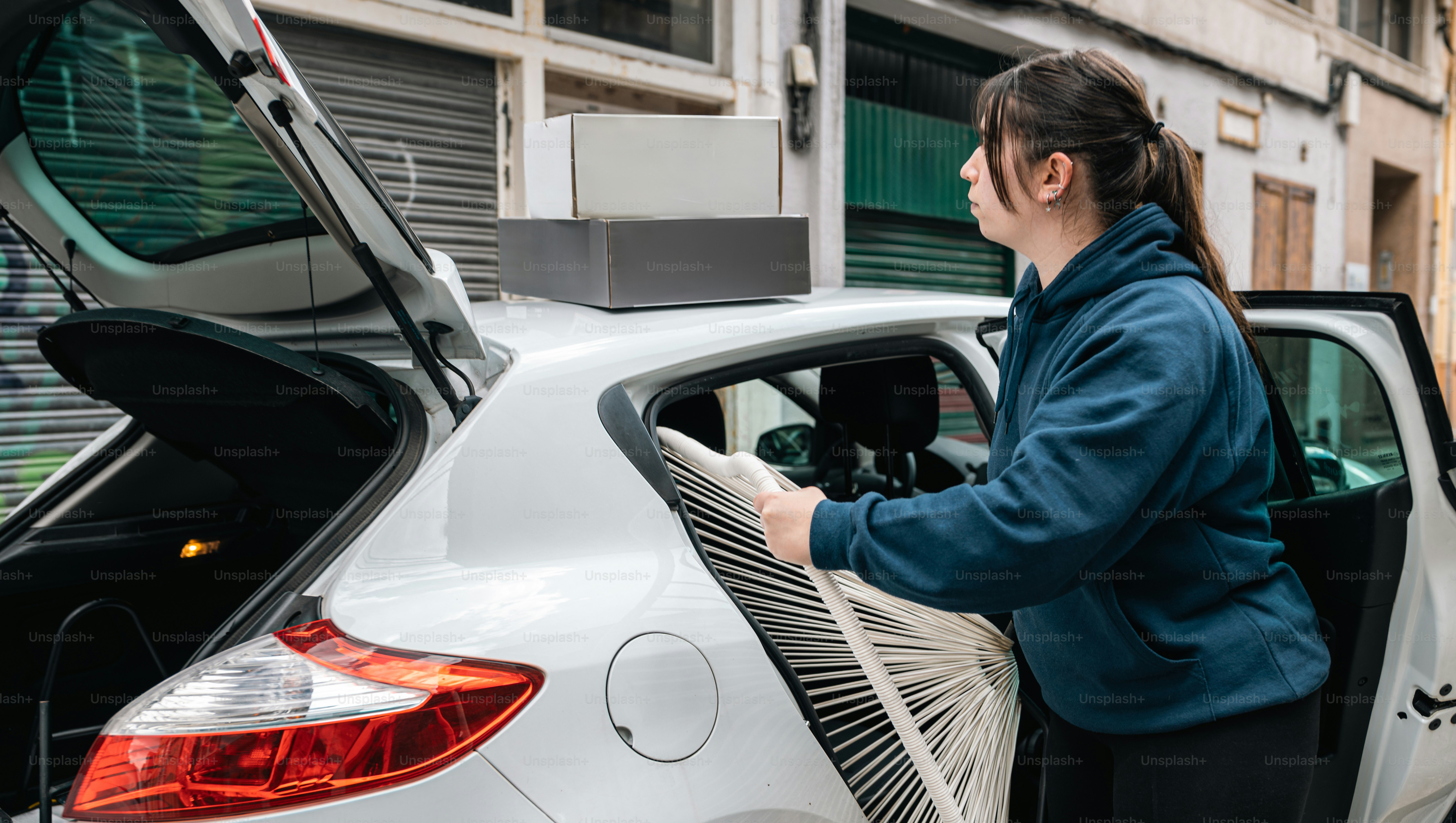 A woman loads boxes into a car. photo – Moving Image on Unsplash