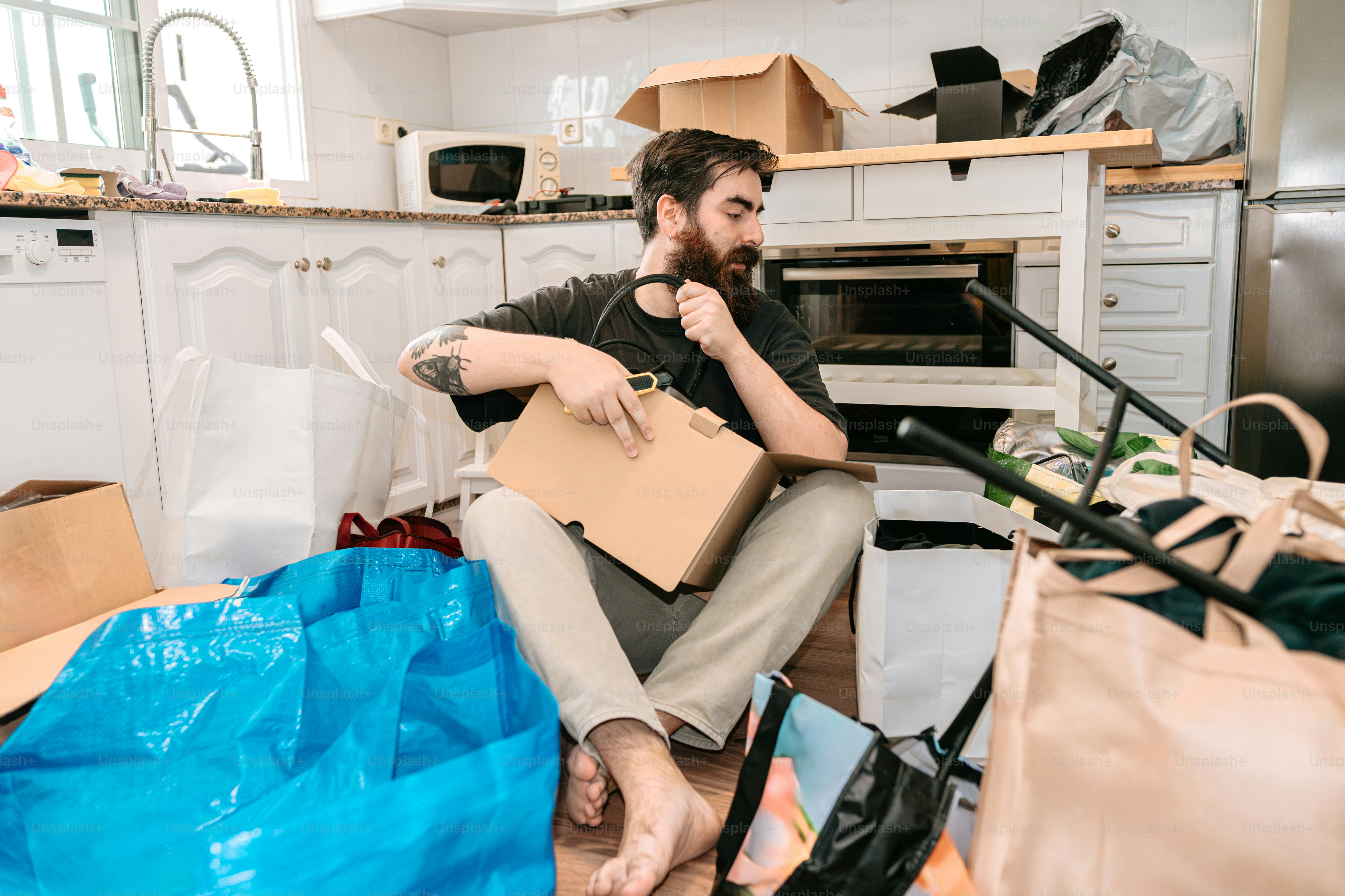 Man sits among moving boxes in a messy kitchen. photo – Home Image on ...