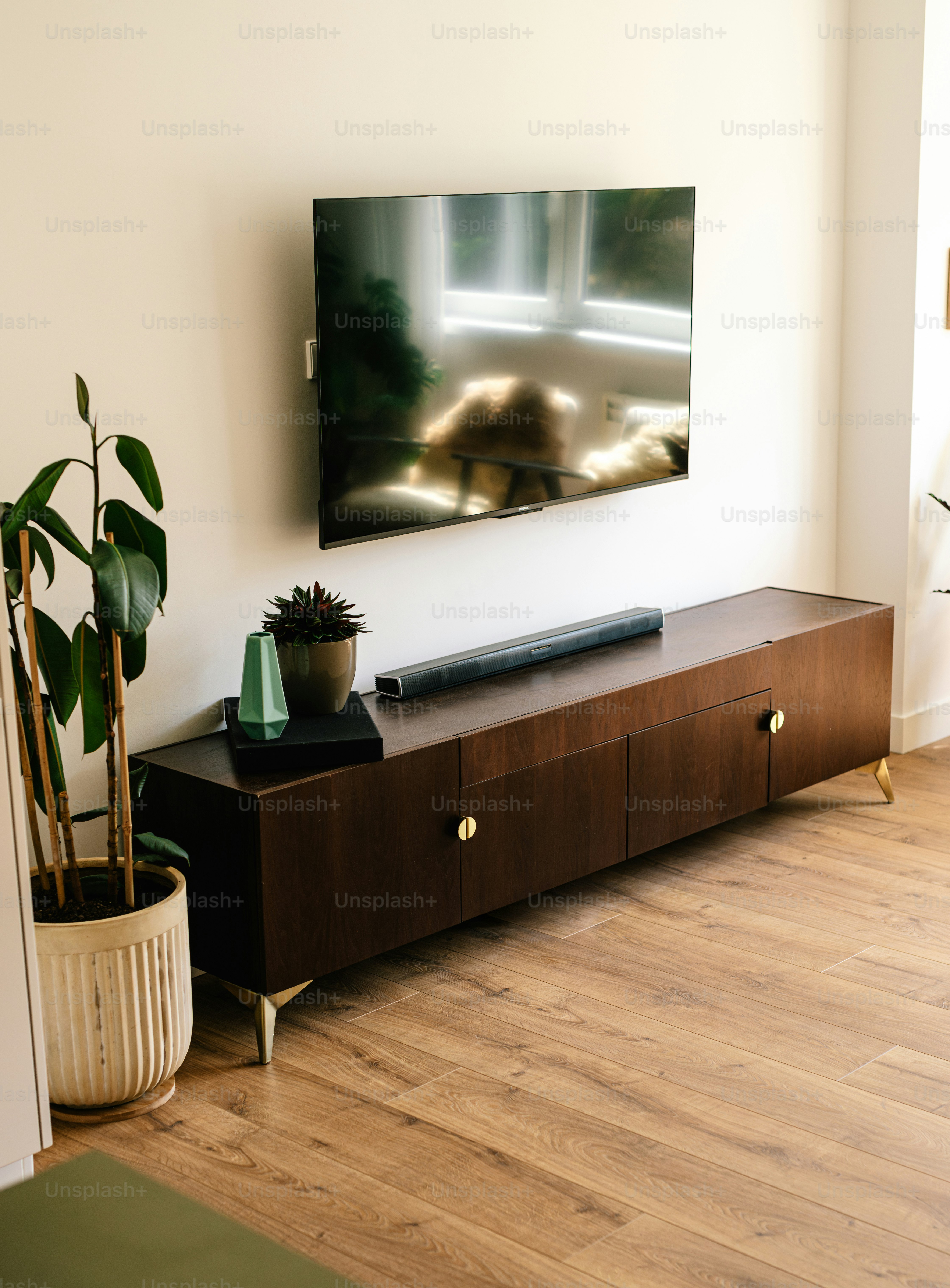 A television is mounted above a wood cabinet. photo – Interior design ...