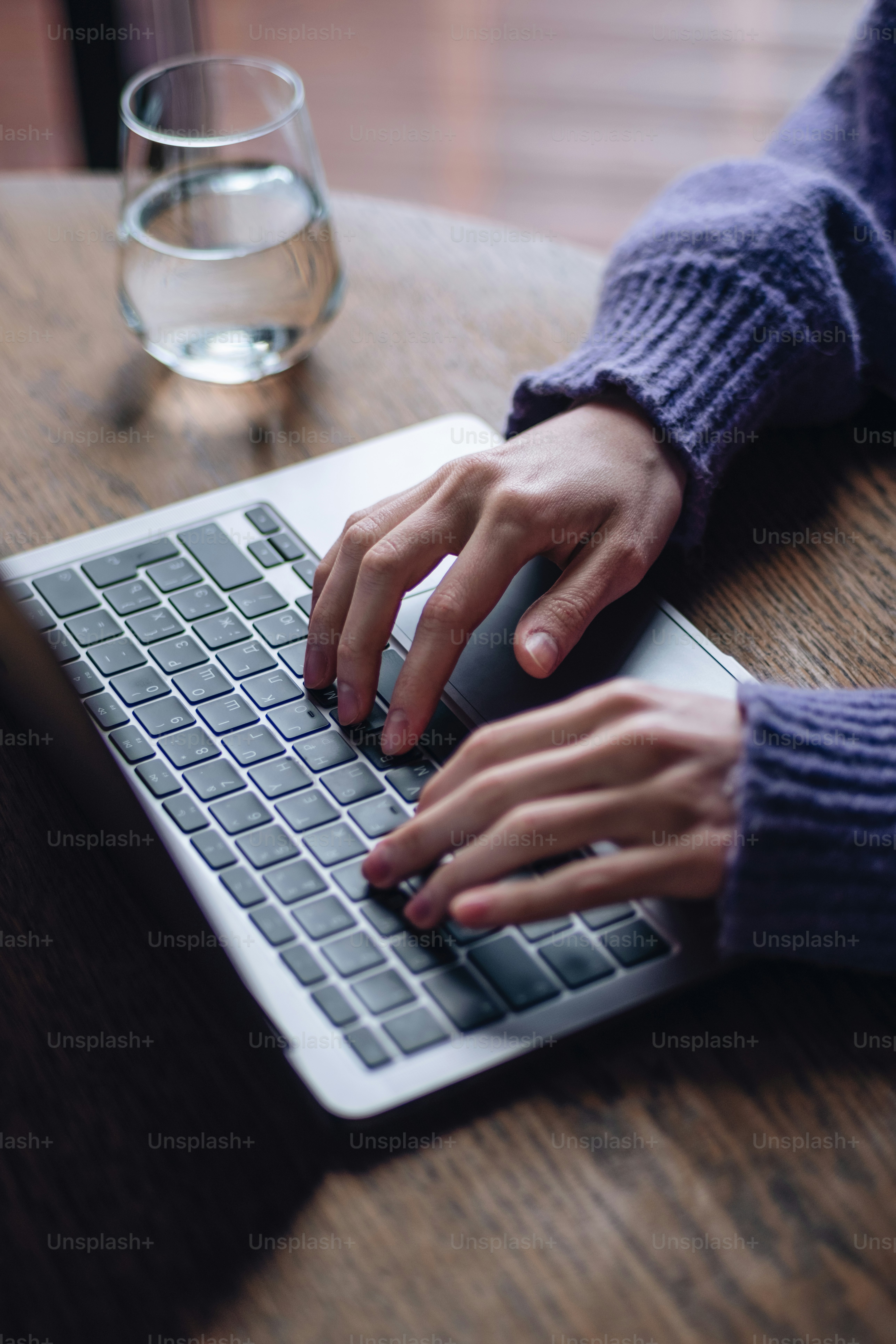 Hands typing on a laptop near a glass of water. photo – Technology ...