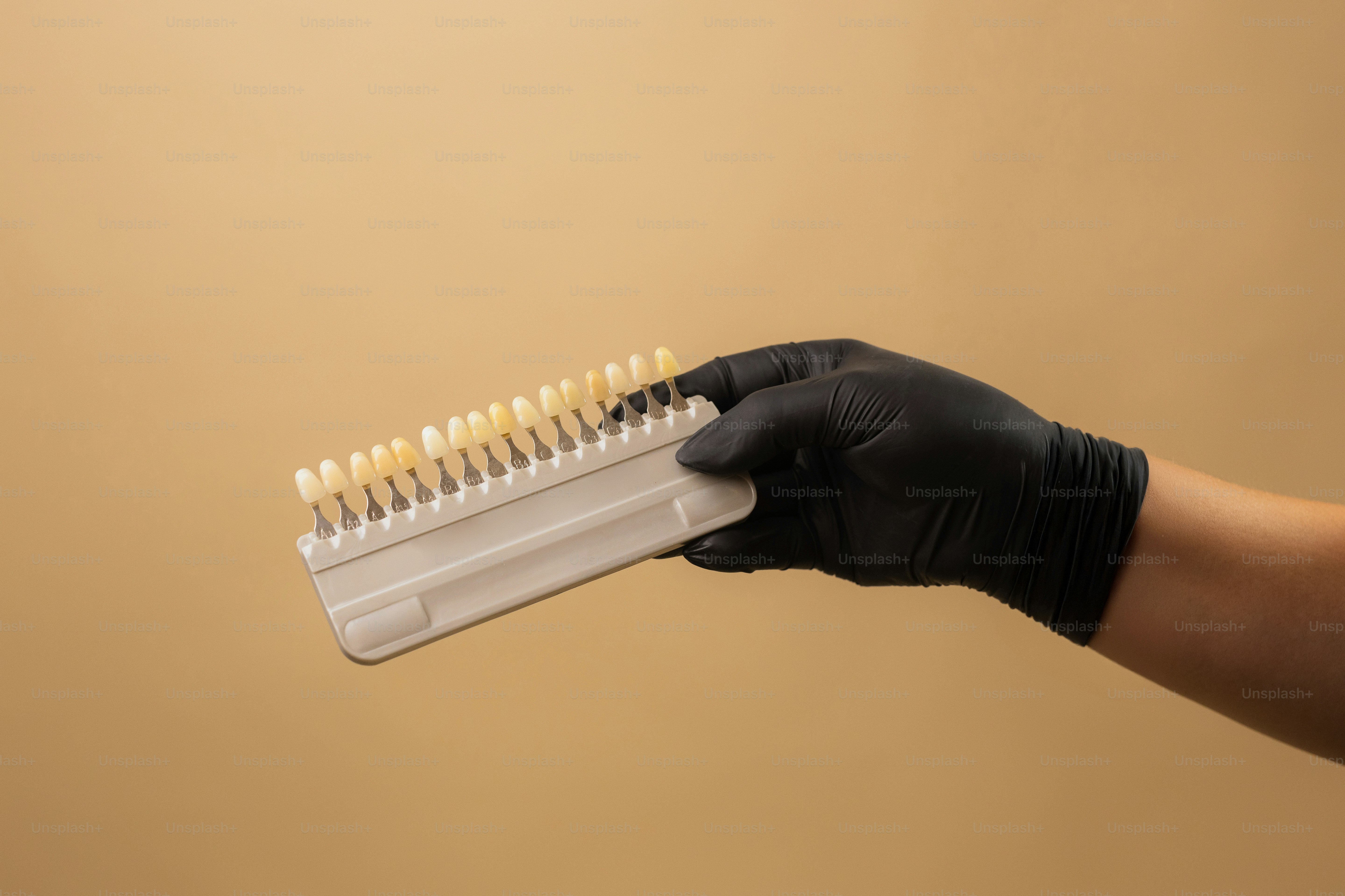 A hand in glove holds a dental shade guide. photo – Dental Image on ...