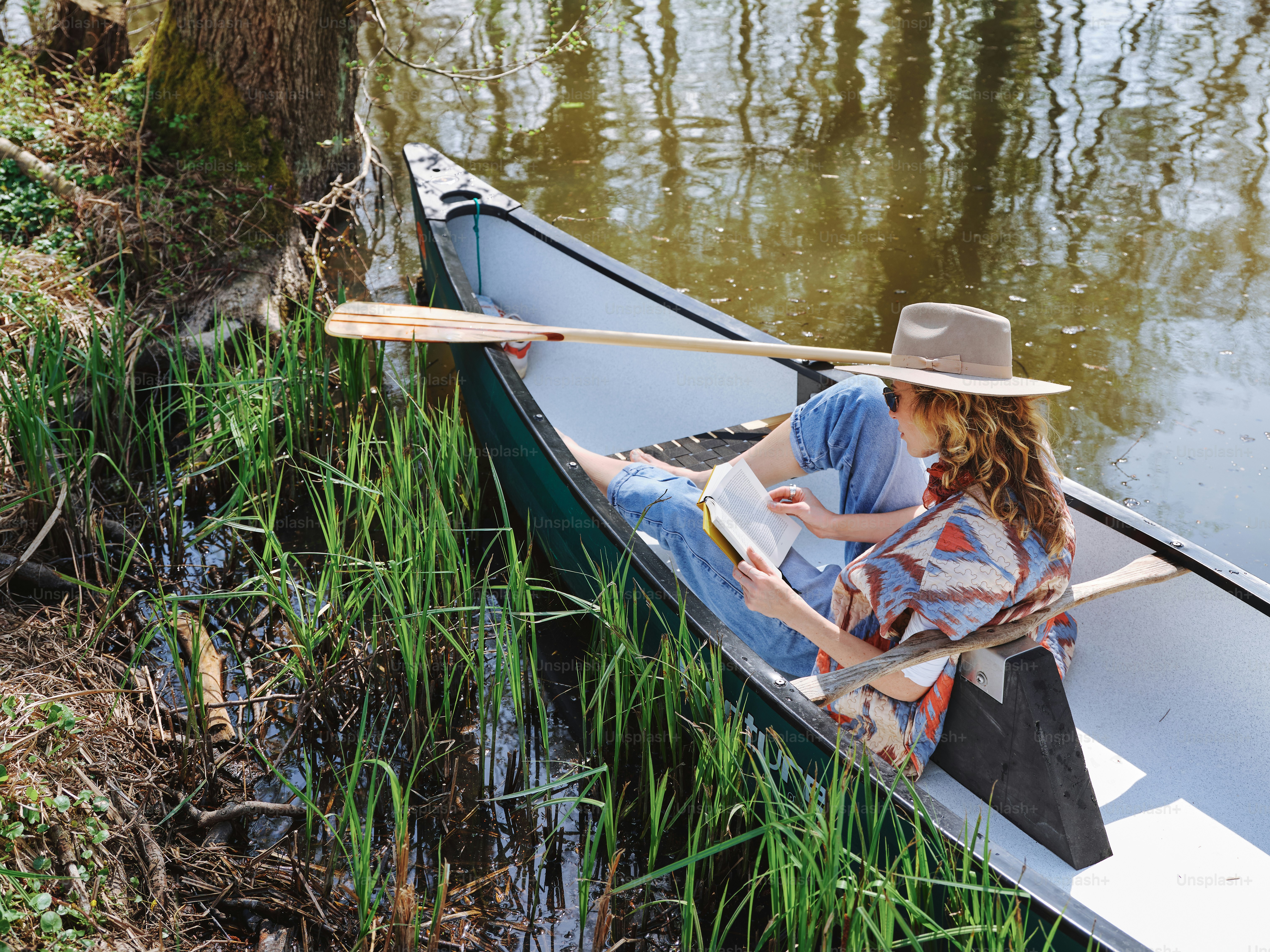 Couple in a canoe enjoy reading by the water. photo – Travel Image on ...