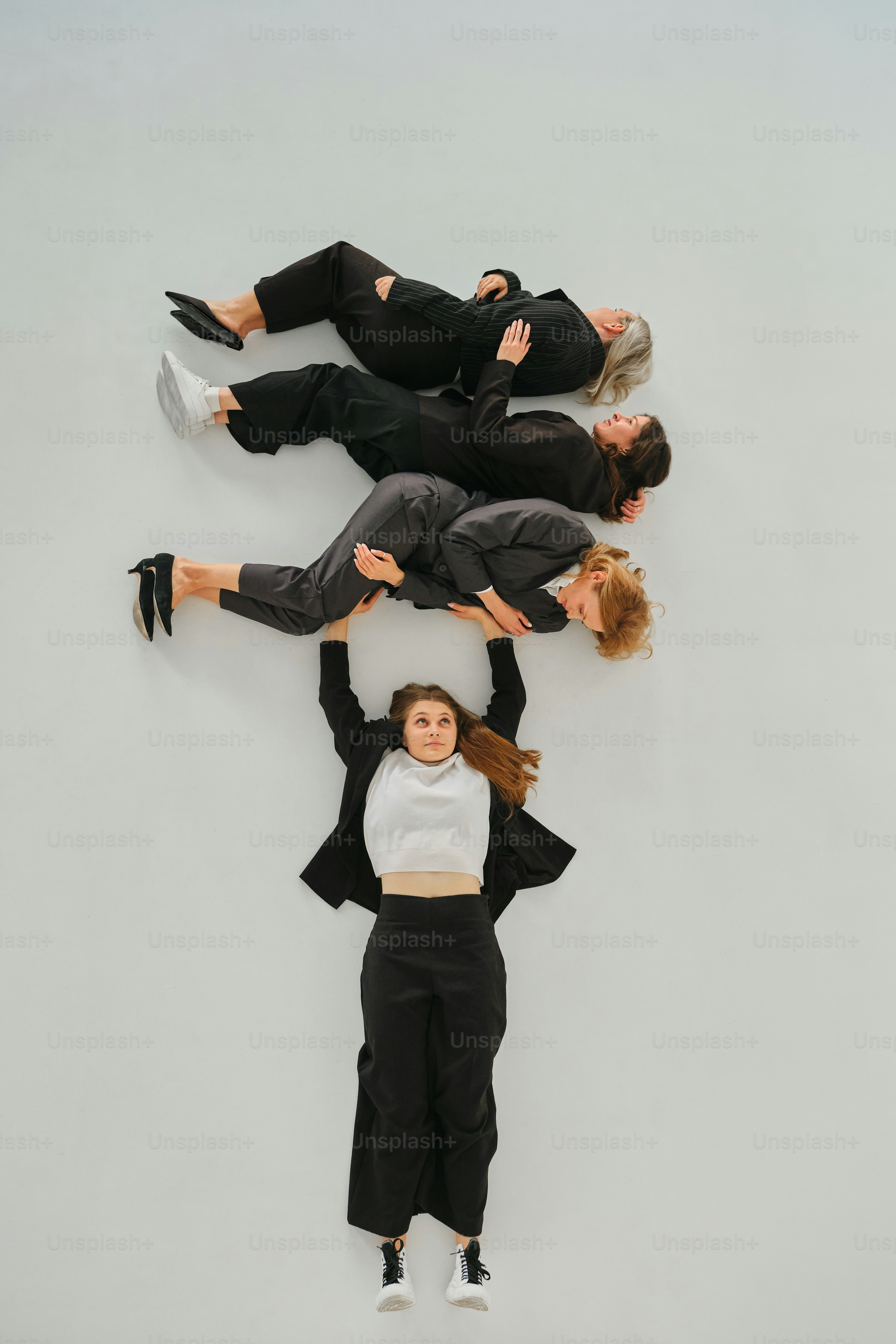 Four women lie down in a body stack. photo – Women Image on Unsplash