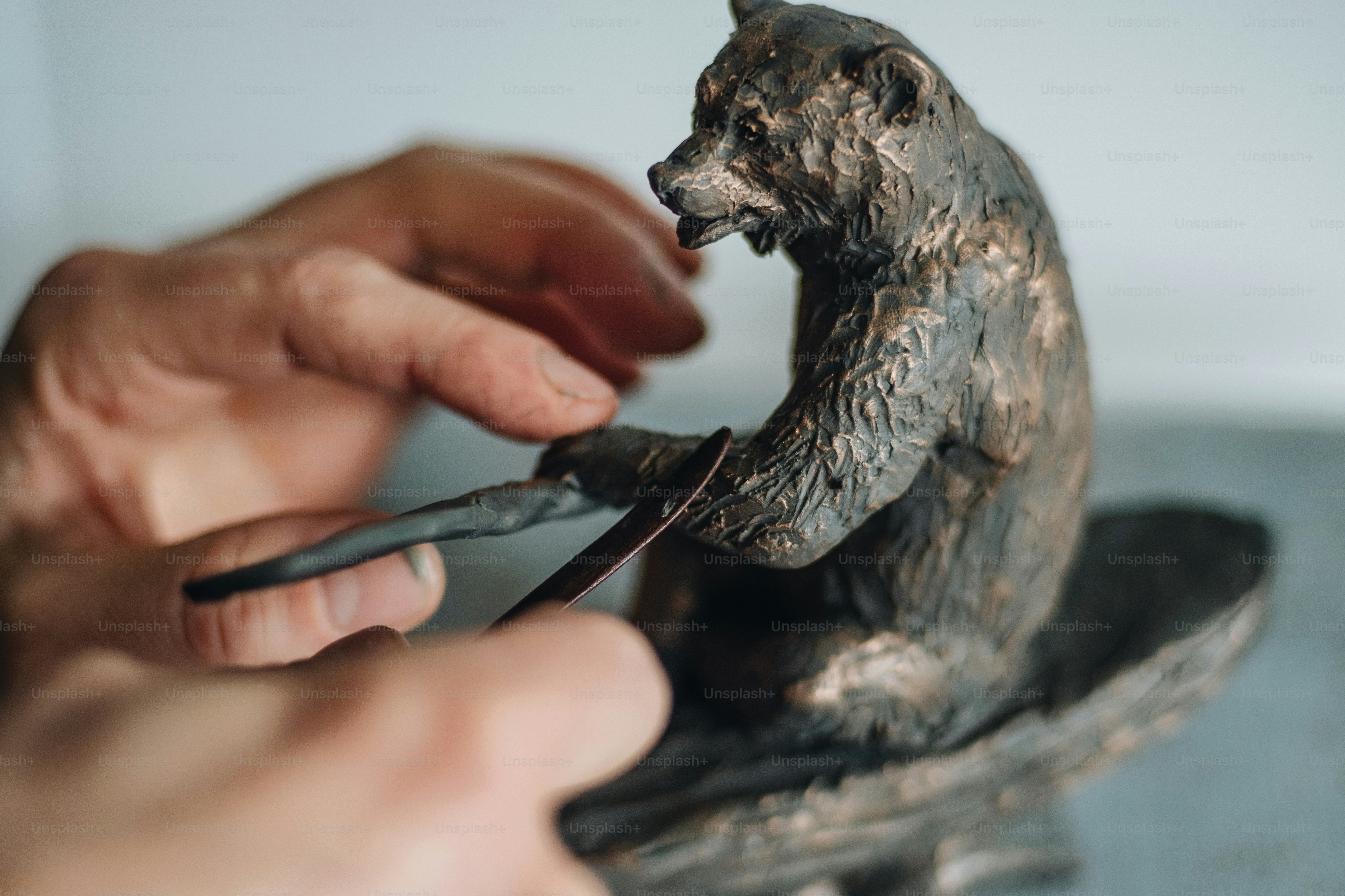 Las manos trabajan en la escultura de un oso, elaborando su forma. foto ...