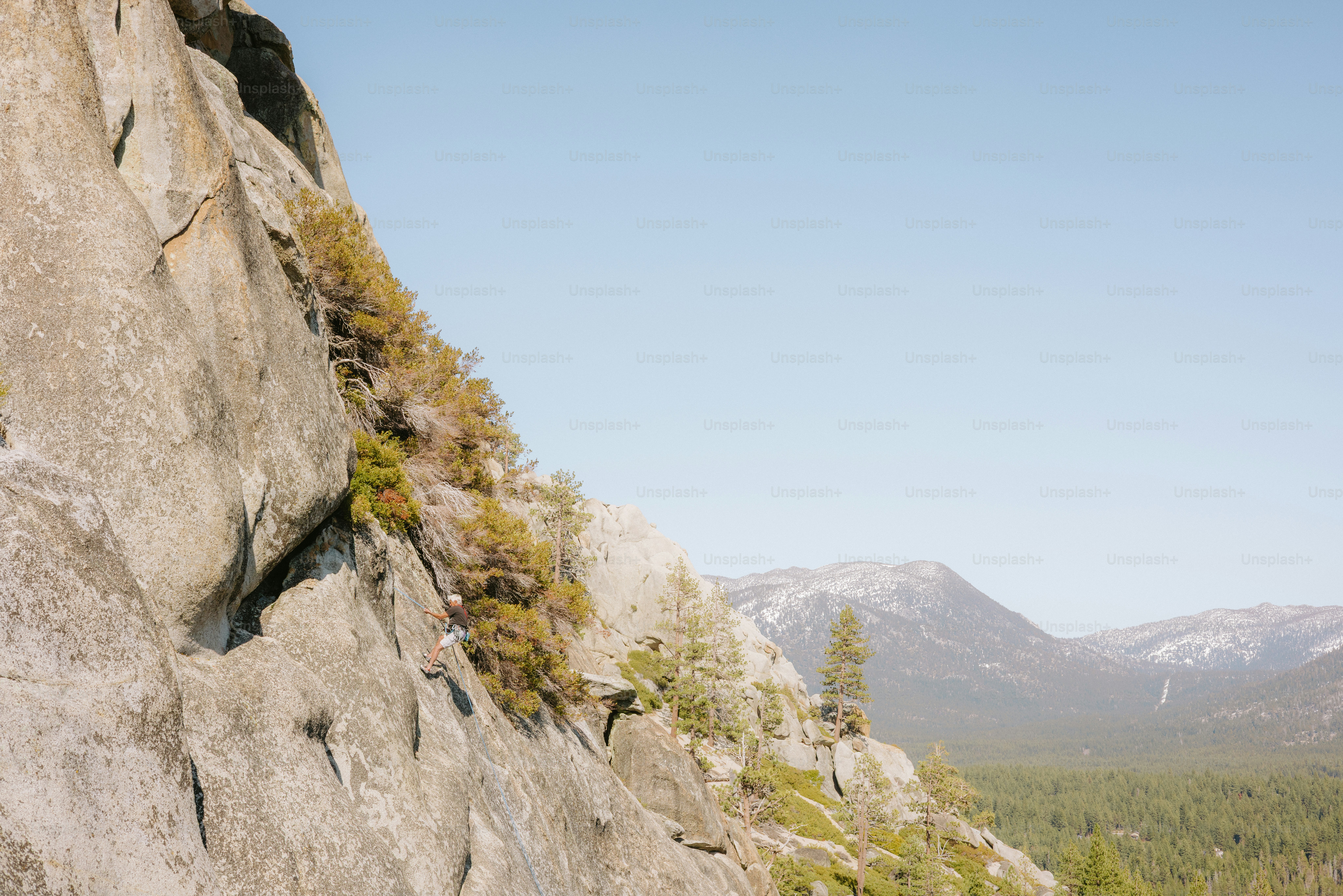 A rocky cliffside with trees and mountains. photo – Mountains Image on ...