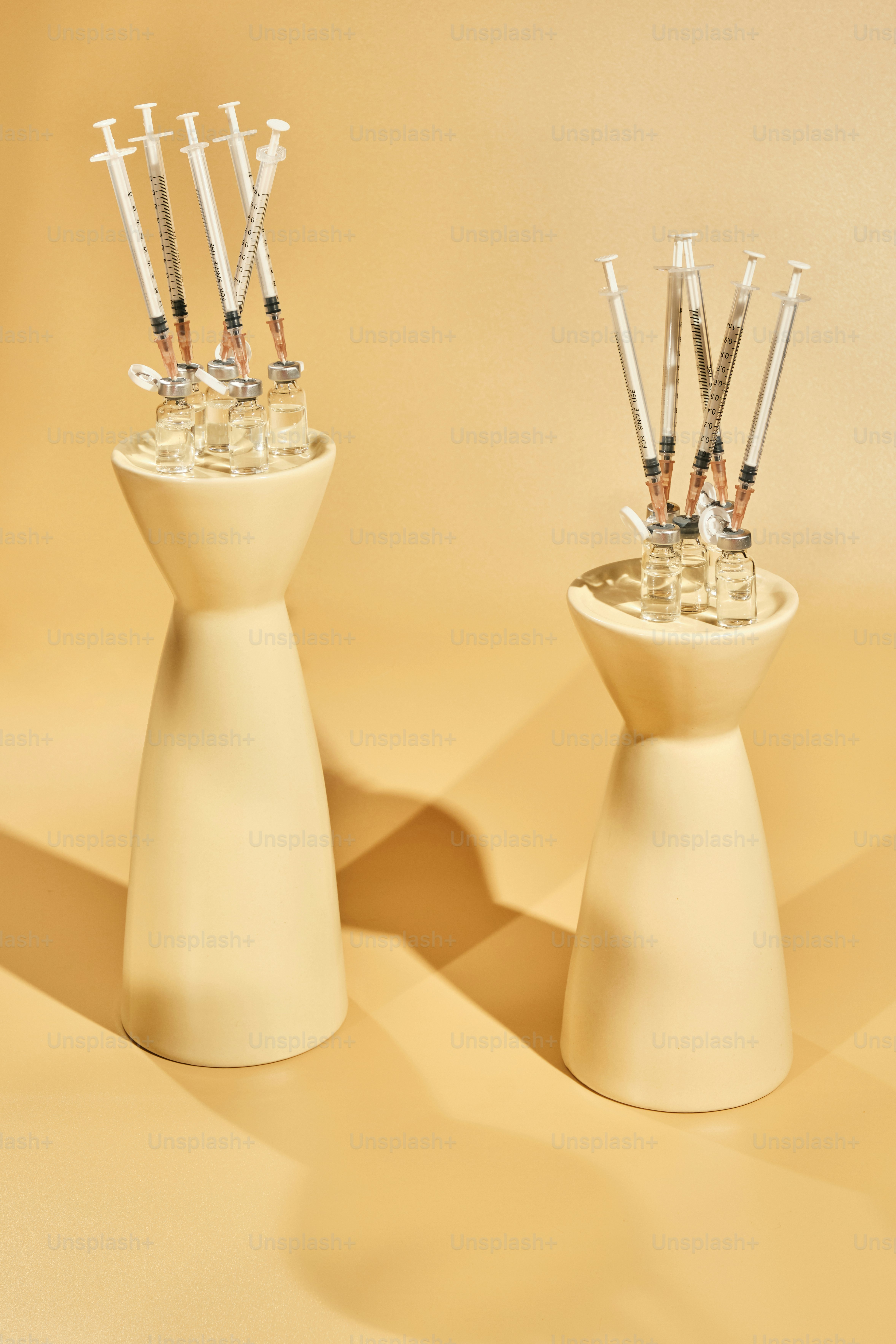 Syringes are in vases against a cream background. photo – Health Image ...