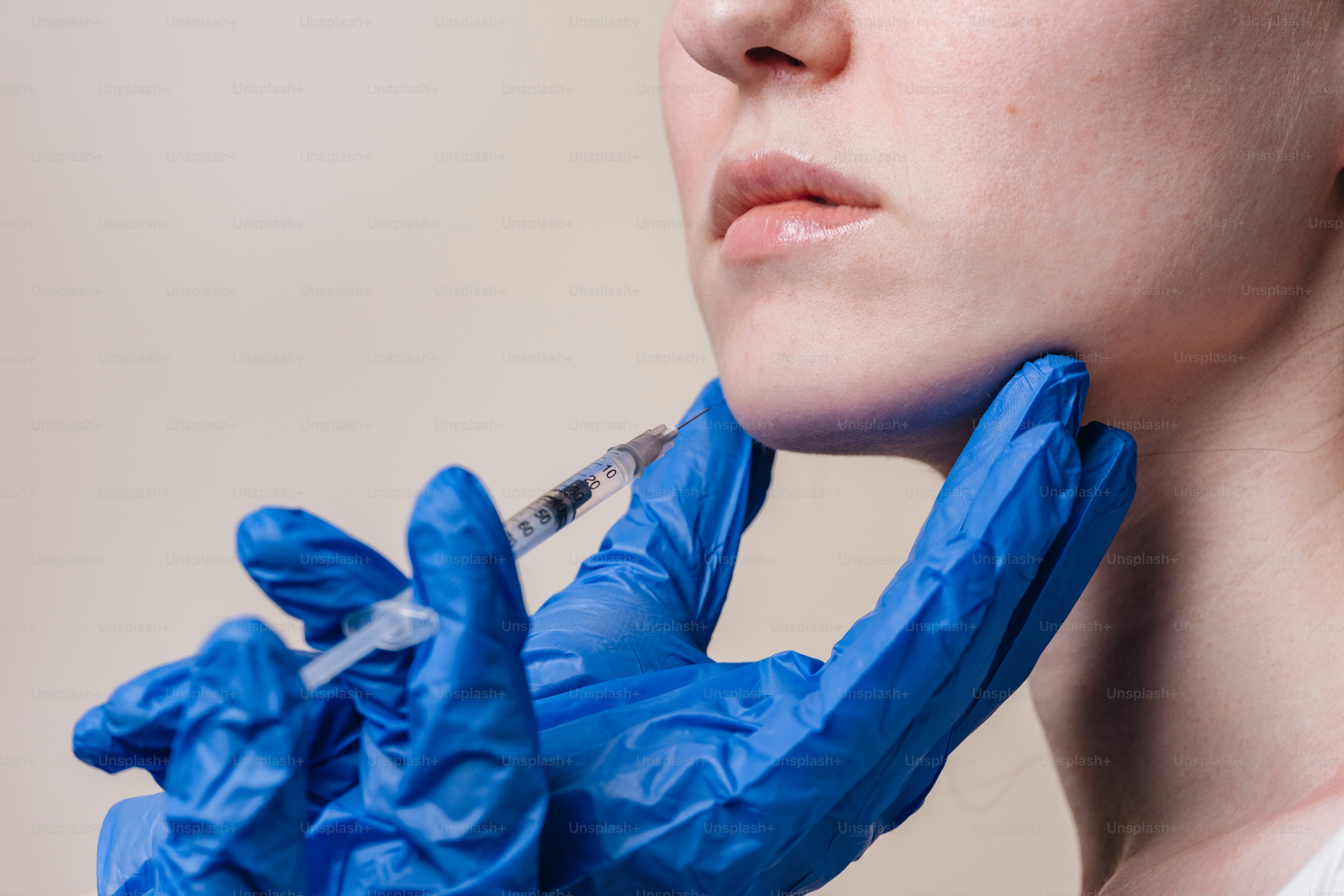 A person receives an injection on their chin. photo – Health Image on ...