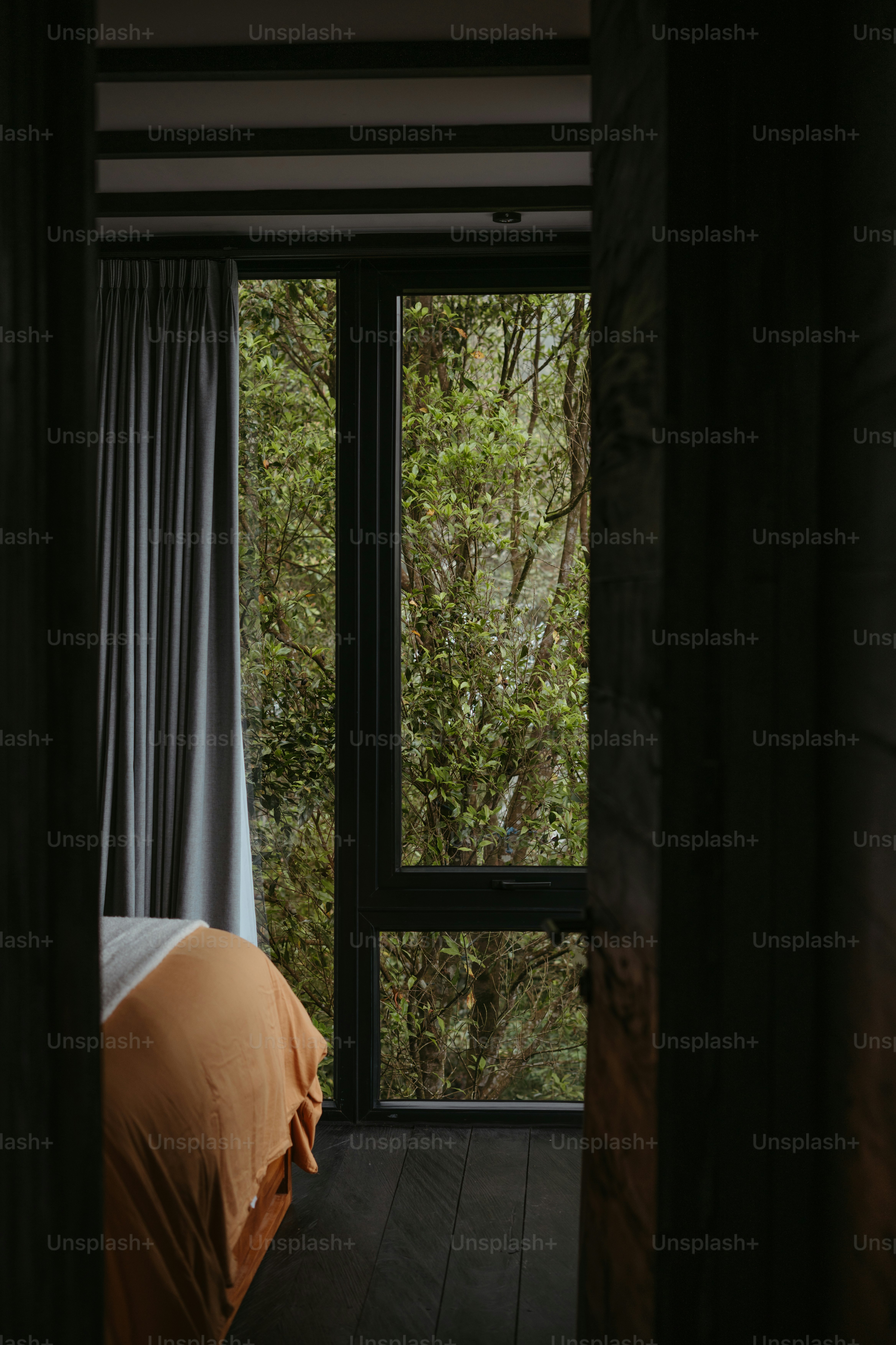 A bedroom window offers a lush green view. photo – Travel Image on Unsplash