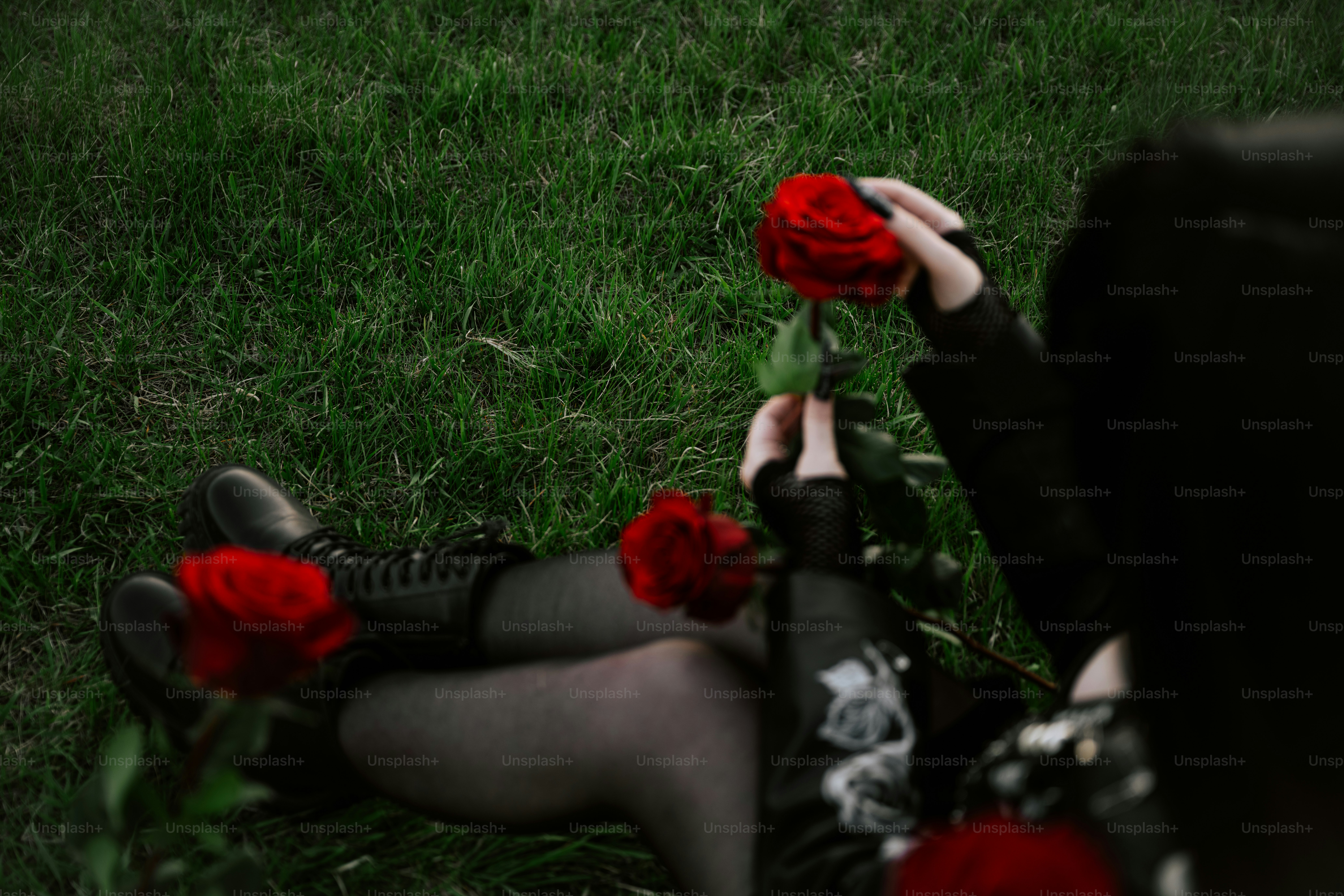 La mujer sostiene rosas rojas mientras está acostada en la hierba. foto ...