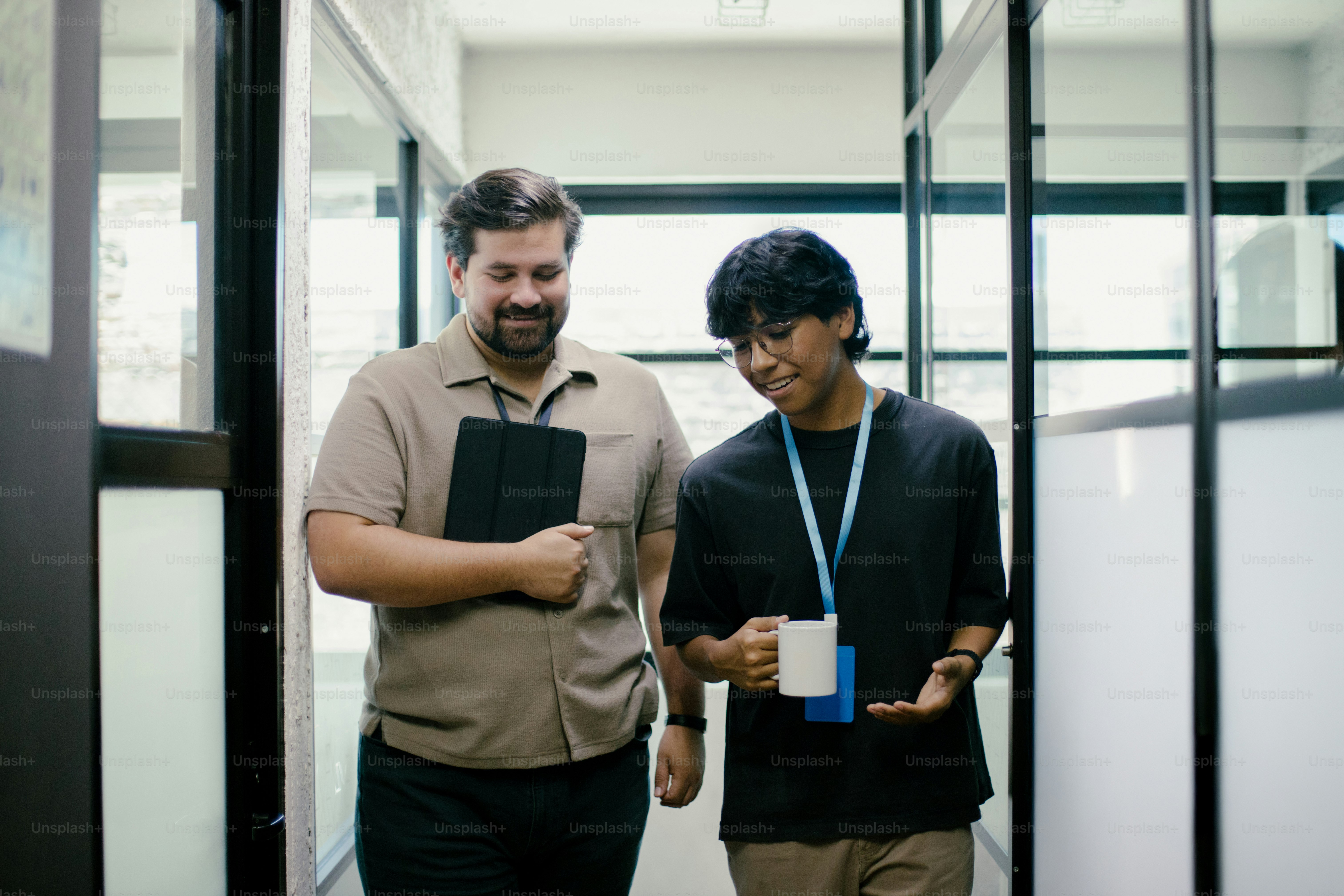 Two people walk and talk in an office corridor. photo – Talking Image ...