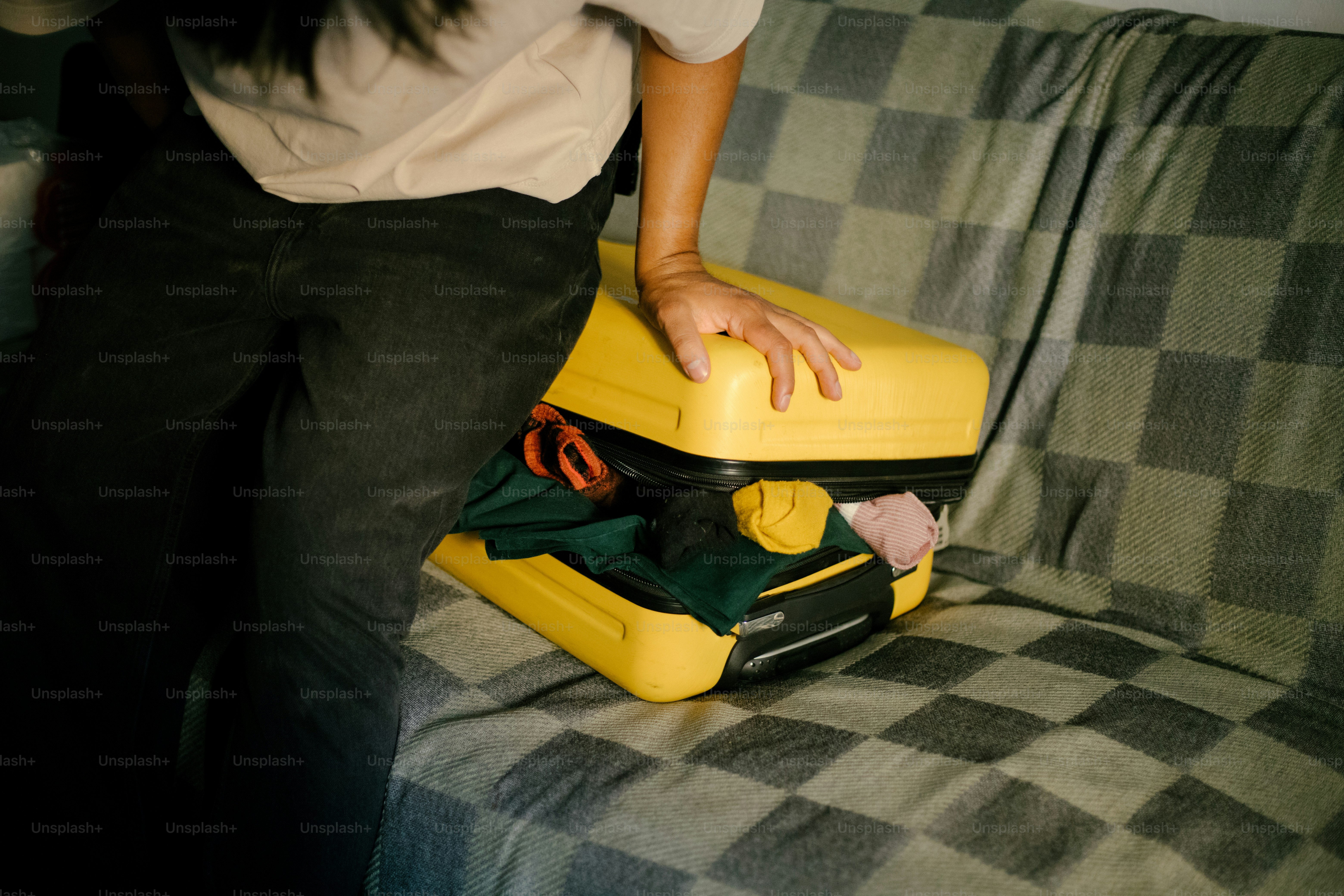 A person is trying to close an overpacked suitcase. photo – Travel ...