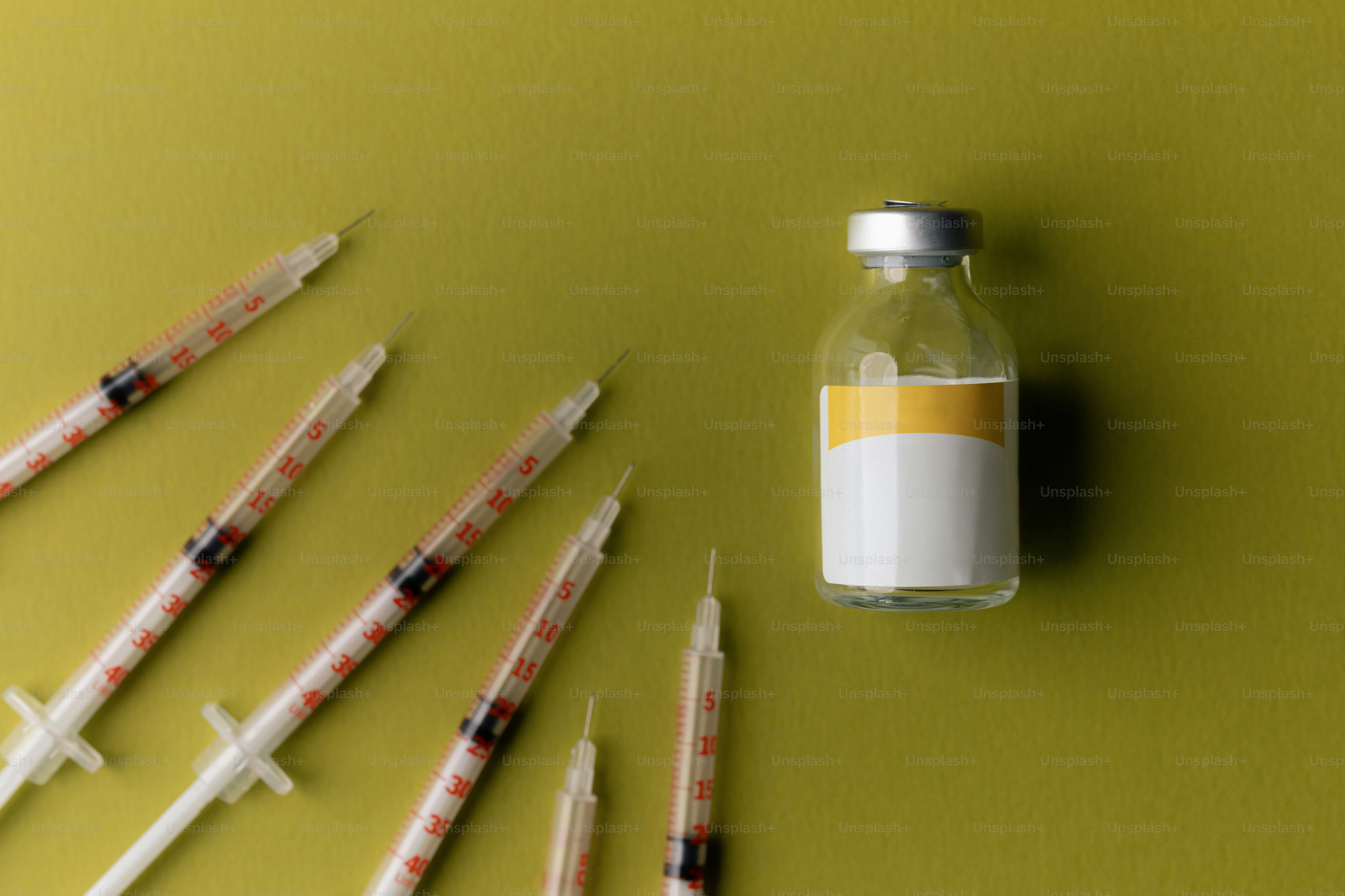 Syringes and a vial sit on a green surface. photo – Health Image on ...