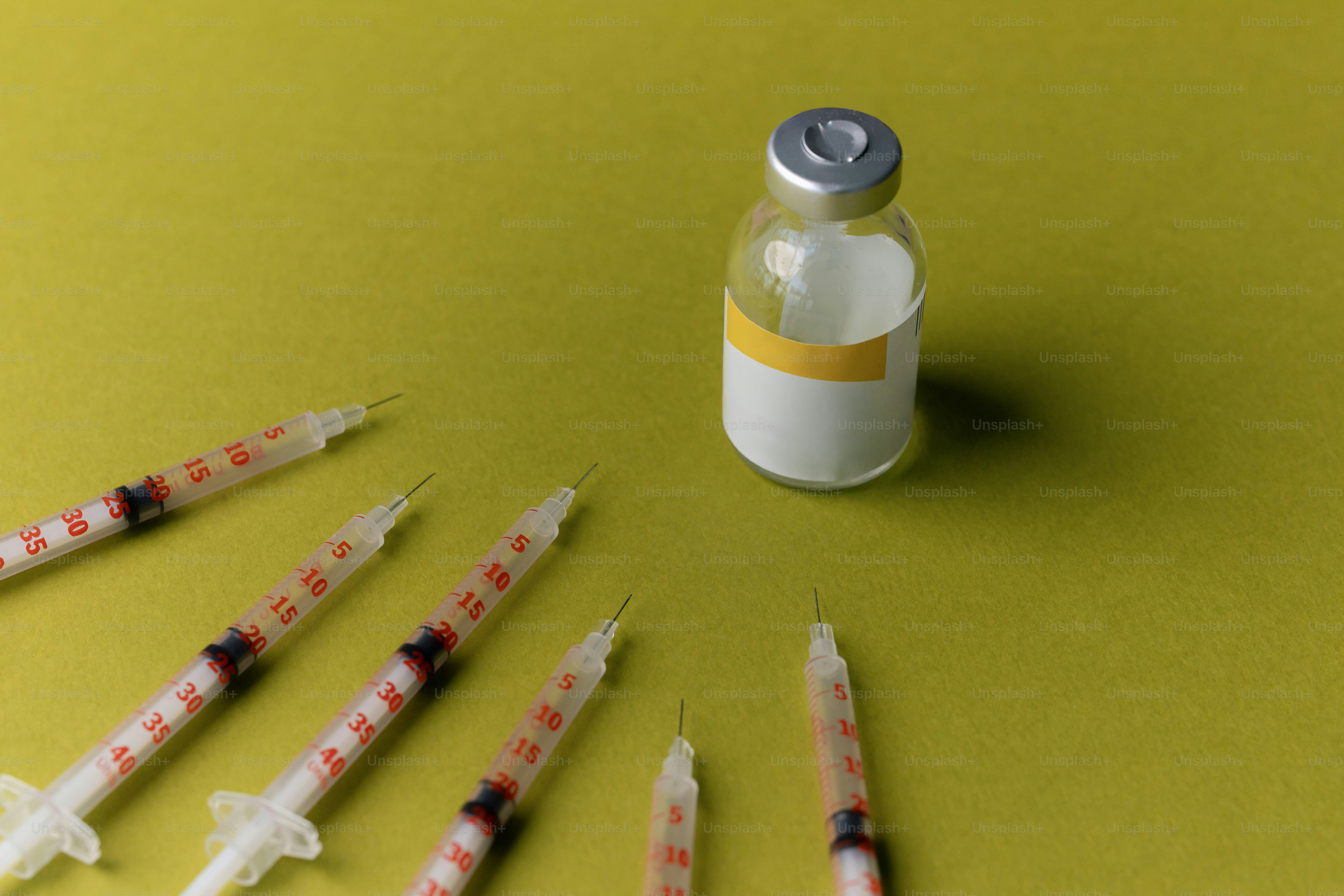 Syringes surround a vial of medication. photo – Health Image on Unsplash