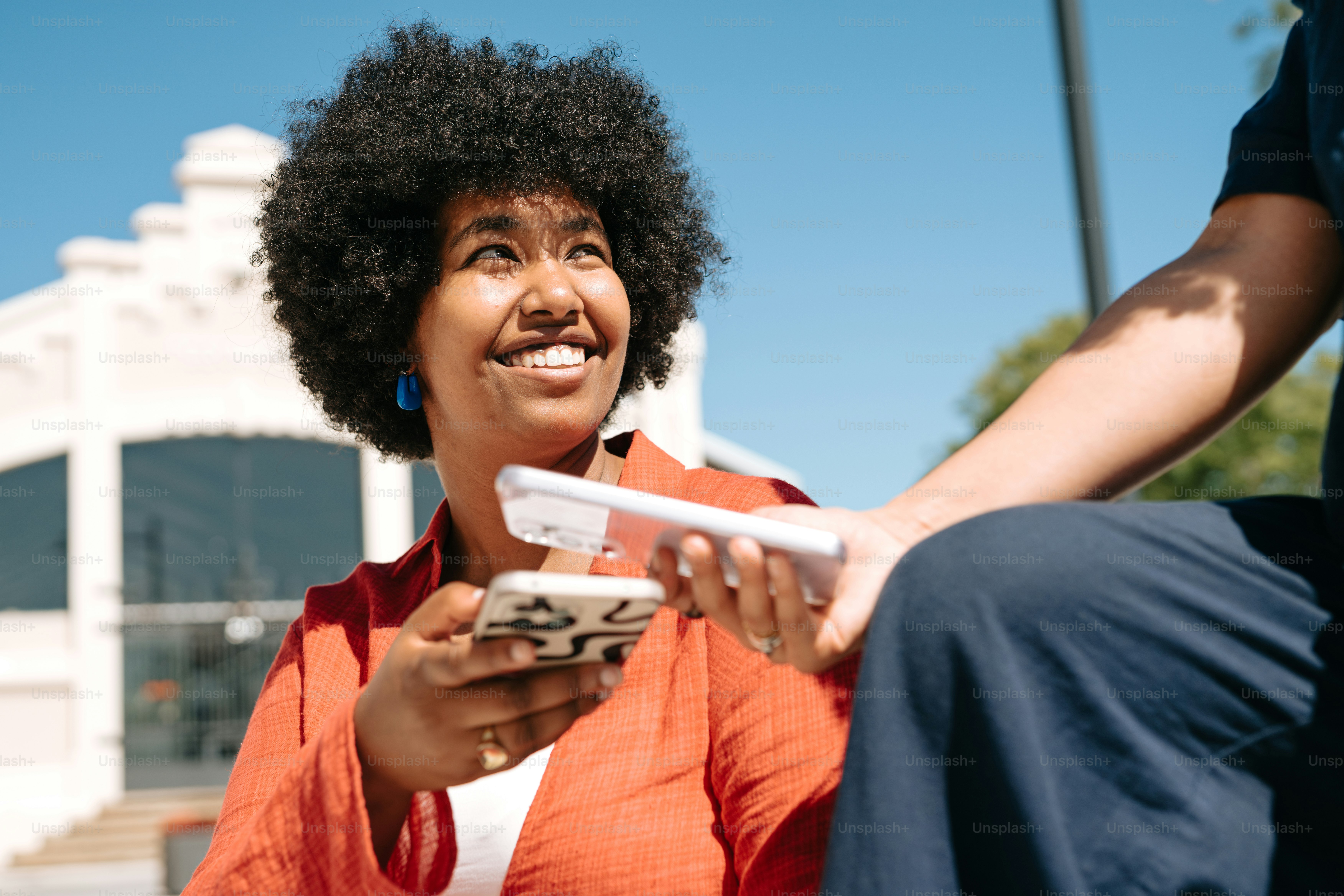 A woman smiles, using her phone outside. photo – Technology Image on ...