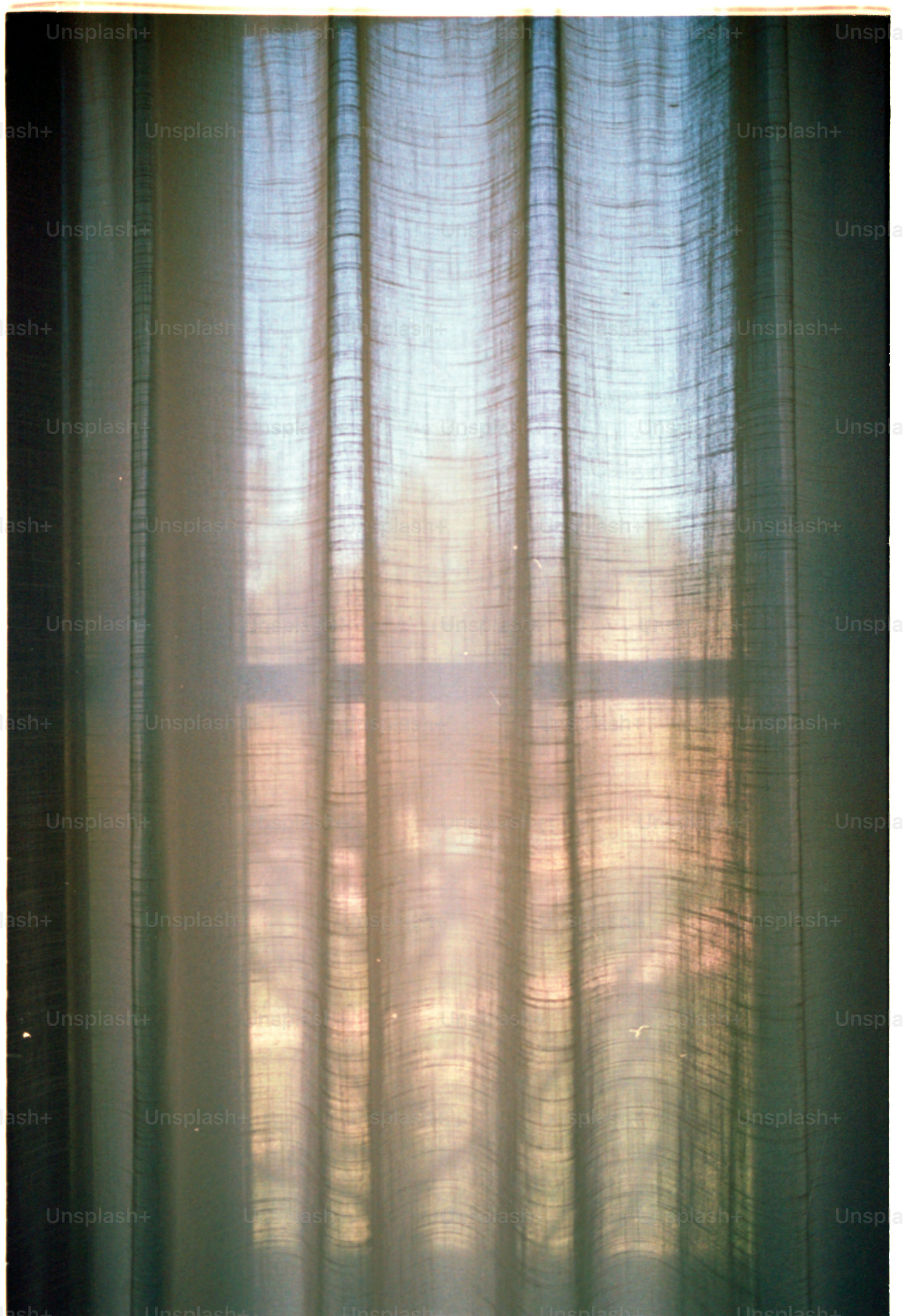 Sheer curtains obscure a sunlit outdoor view. photo – Image on Unsplash