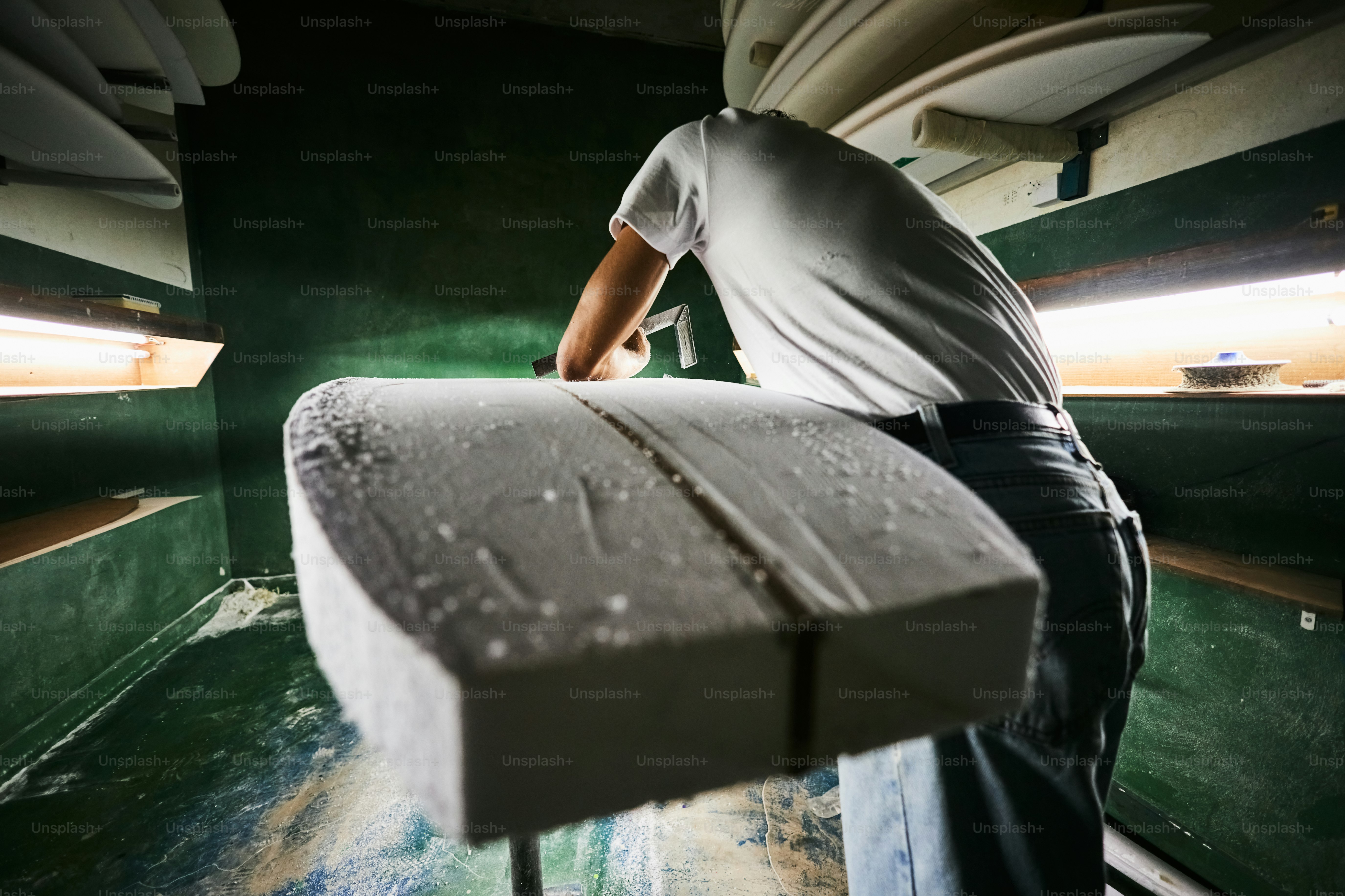 Una persona está dando forma a una tabla de surf con una herramienta ...