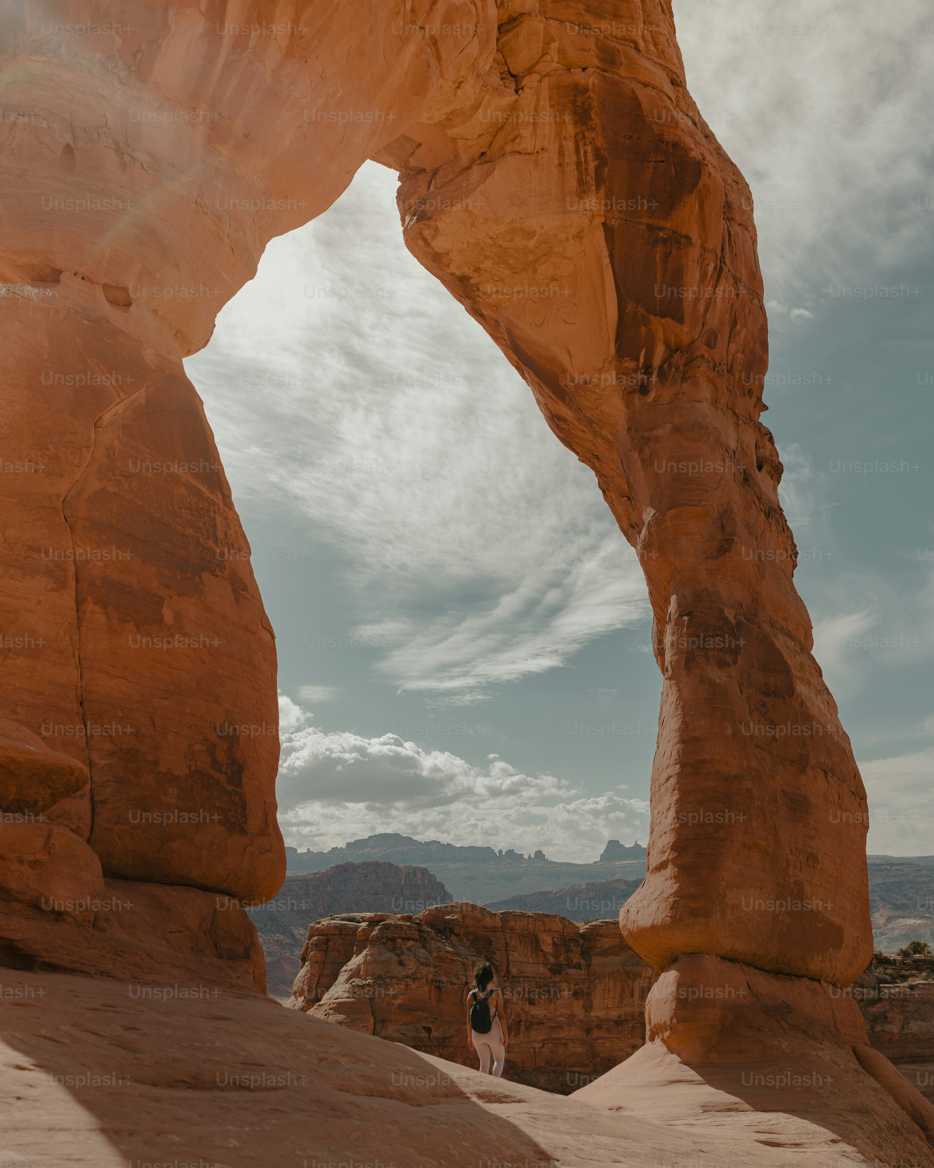 Person stands under a stunning rock arch. photo – Outdoor Image on Unsplash