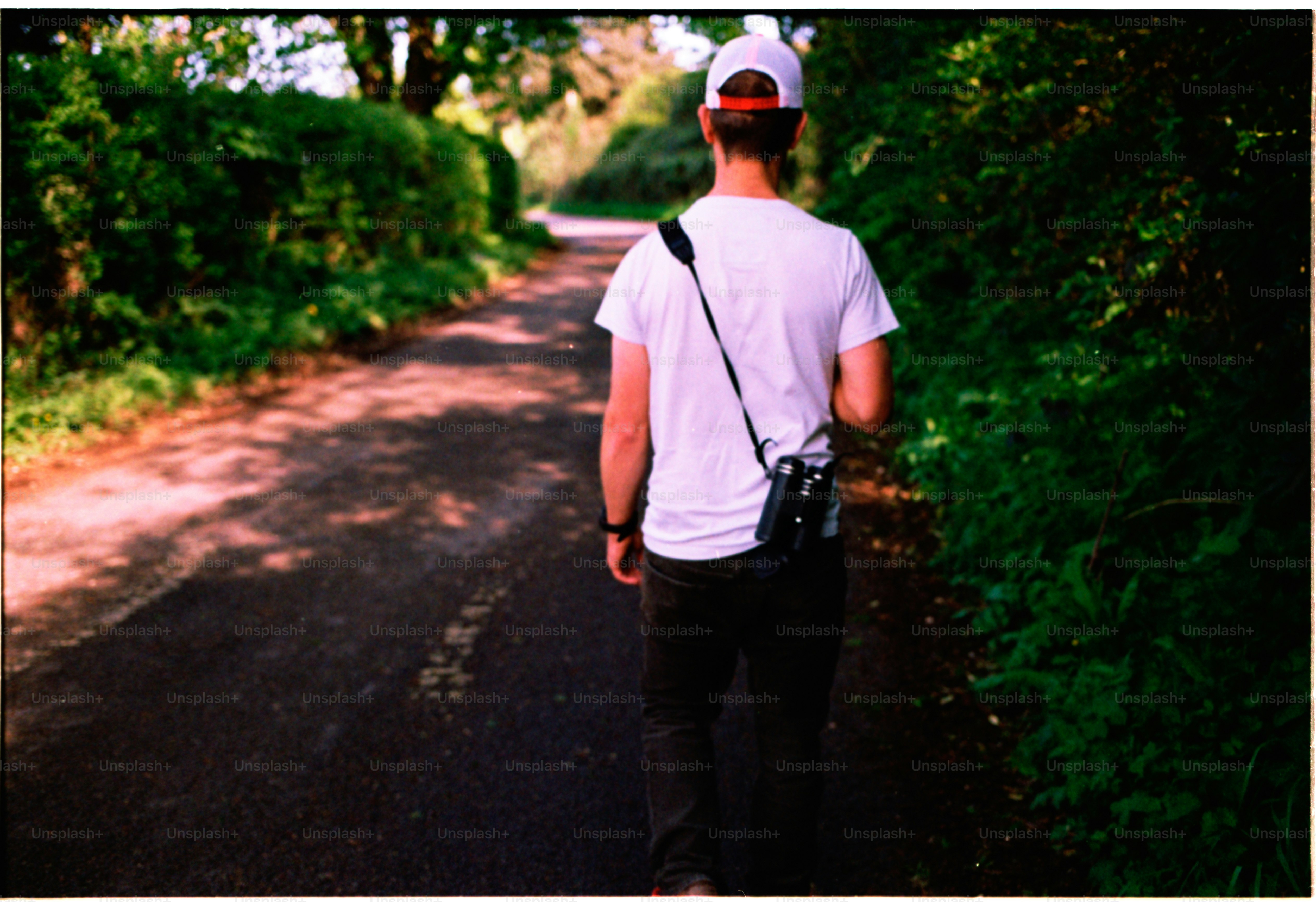 A man walks down a road with a camera. photo – Man Image on Unsplash