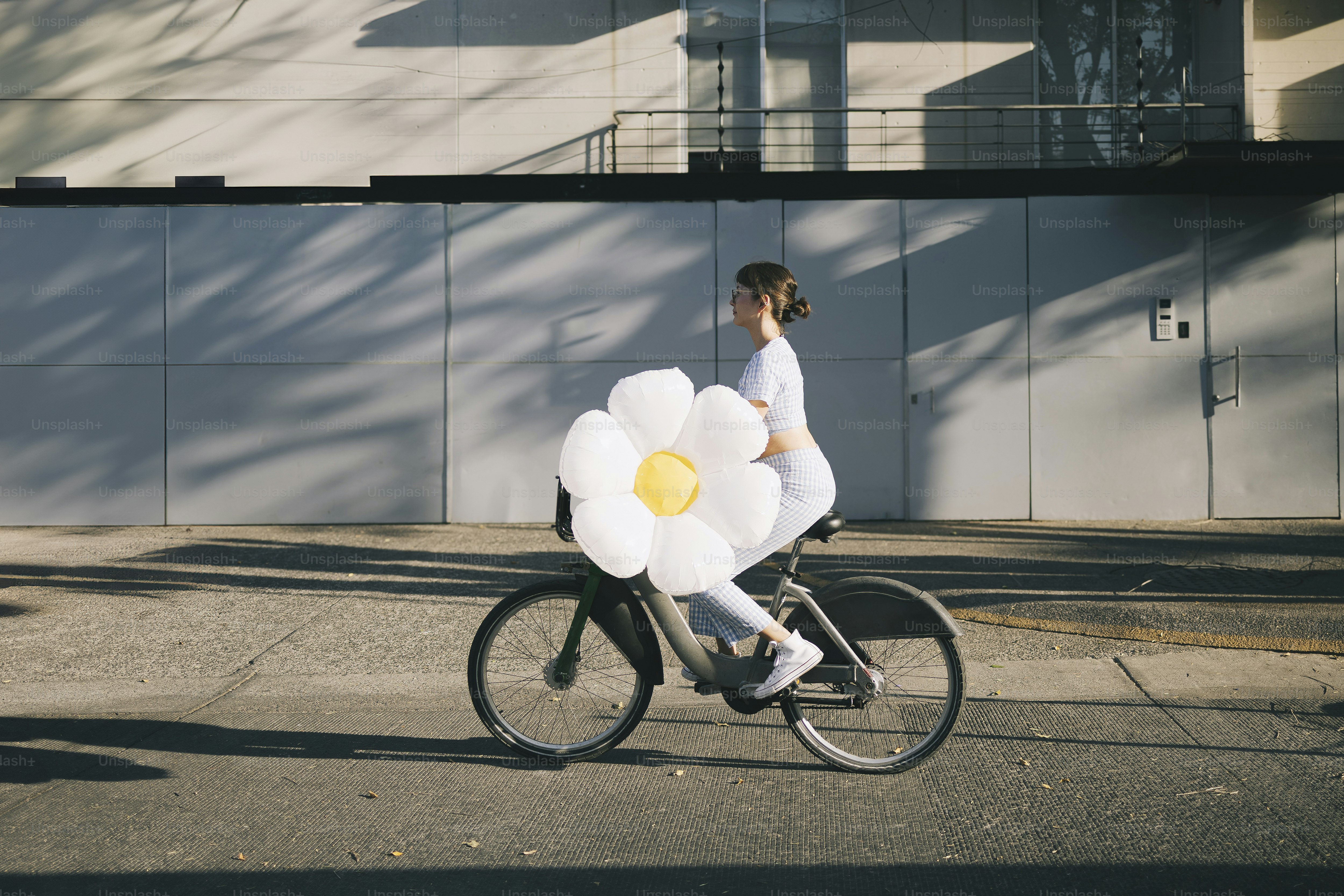A person rides a bike with a giant flower. photo – Flower Image on Unsplash