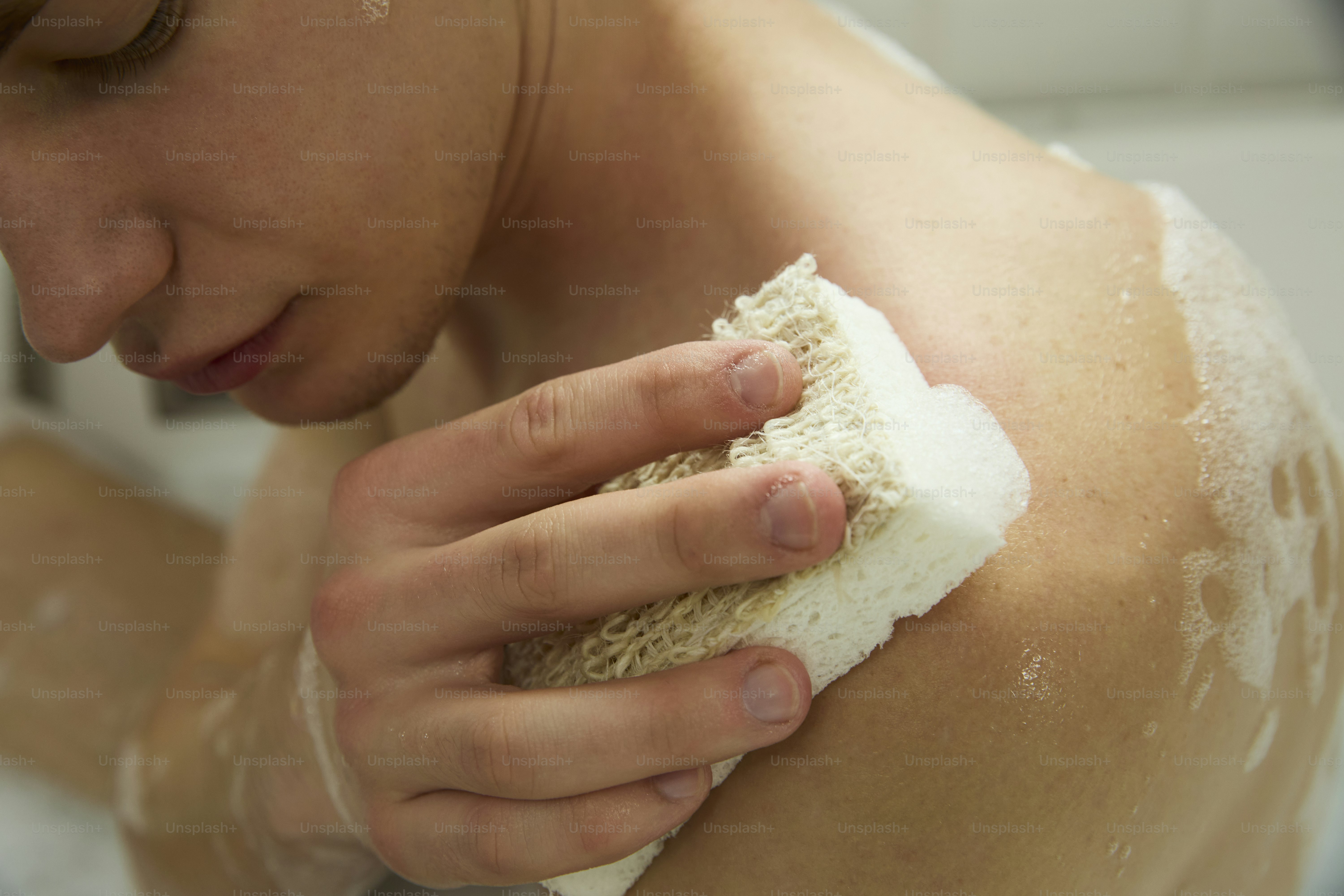 A person is washing their shoulder with a sponge. photo – Bathroom ...