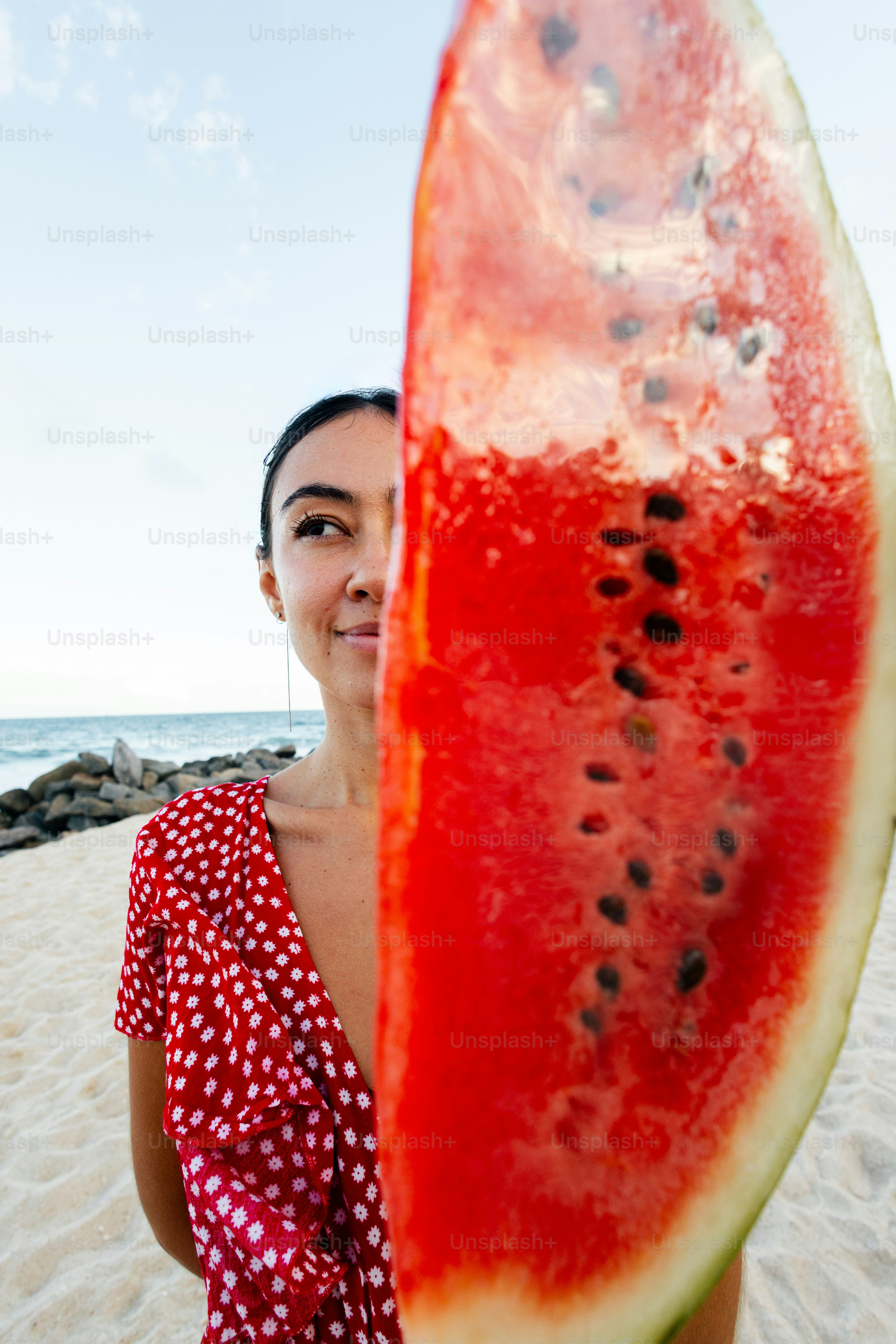 A woman holds a watermelon slice at the beach. photo – Watermelon Image ...