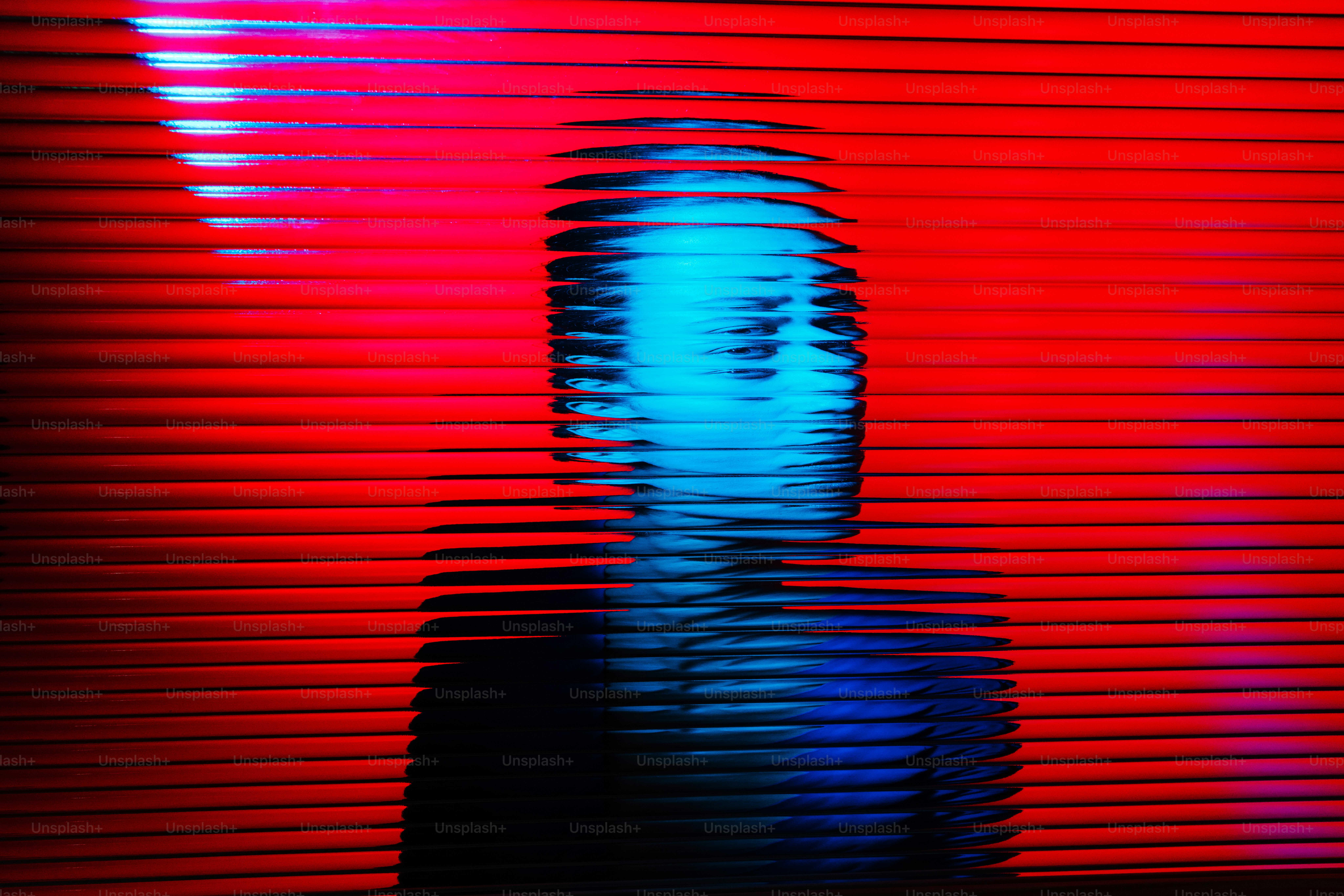 A blue figure stands before a red, blurry background. photo – Portrait ...
