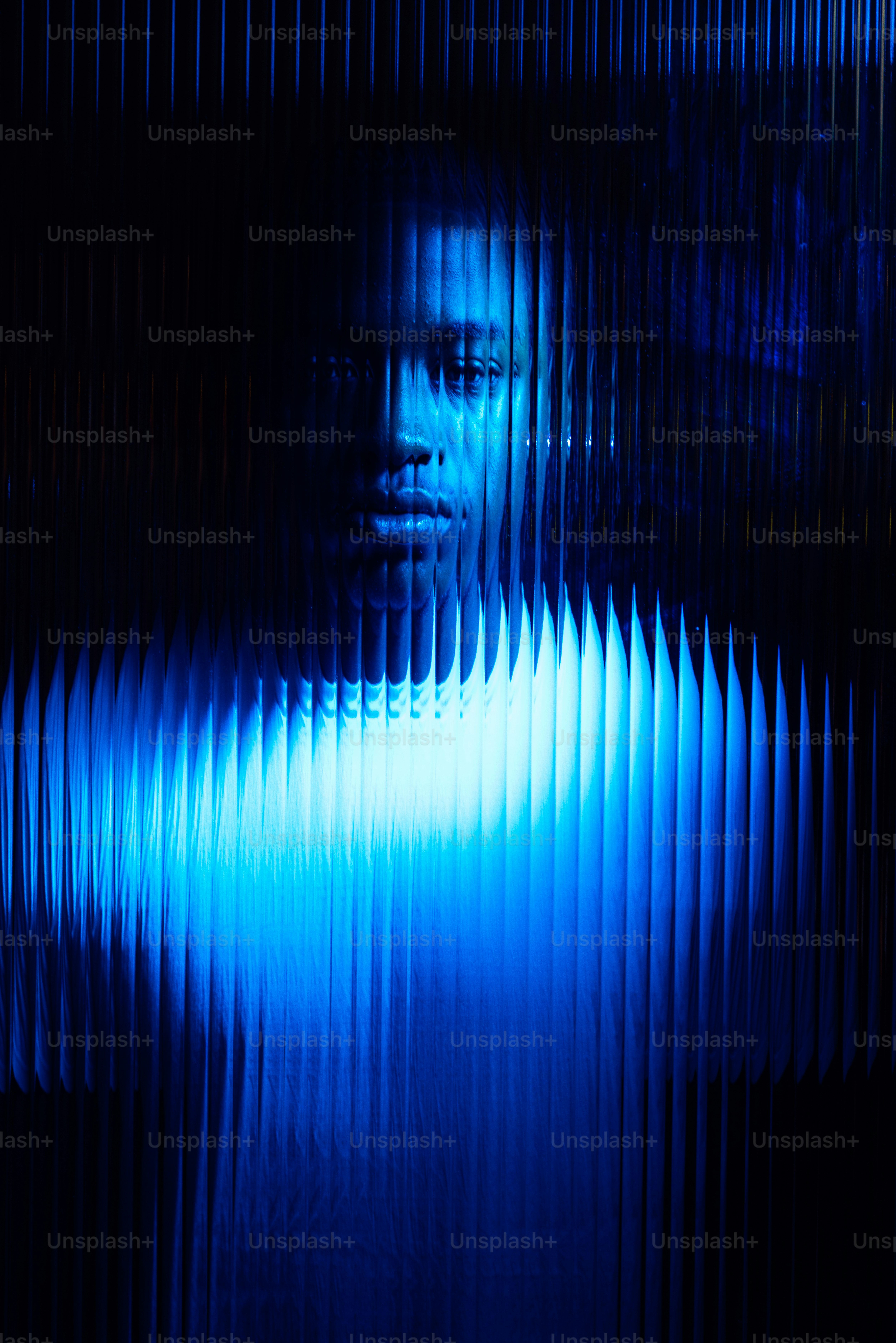 A person looks through a textured, blue barrier. photo – Experimental ...
