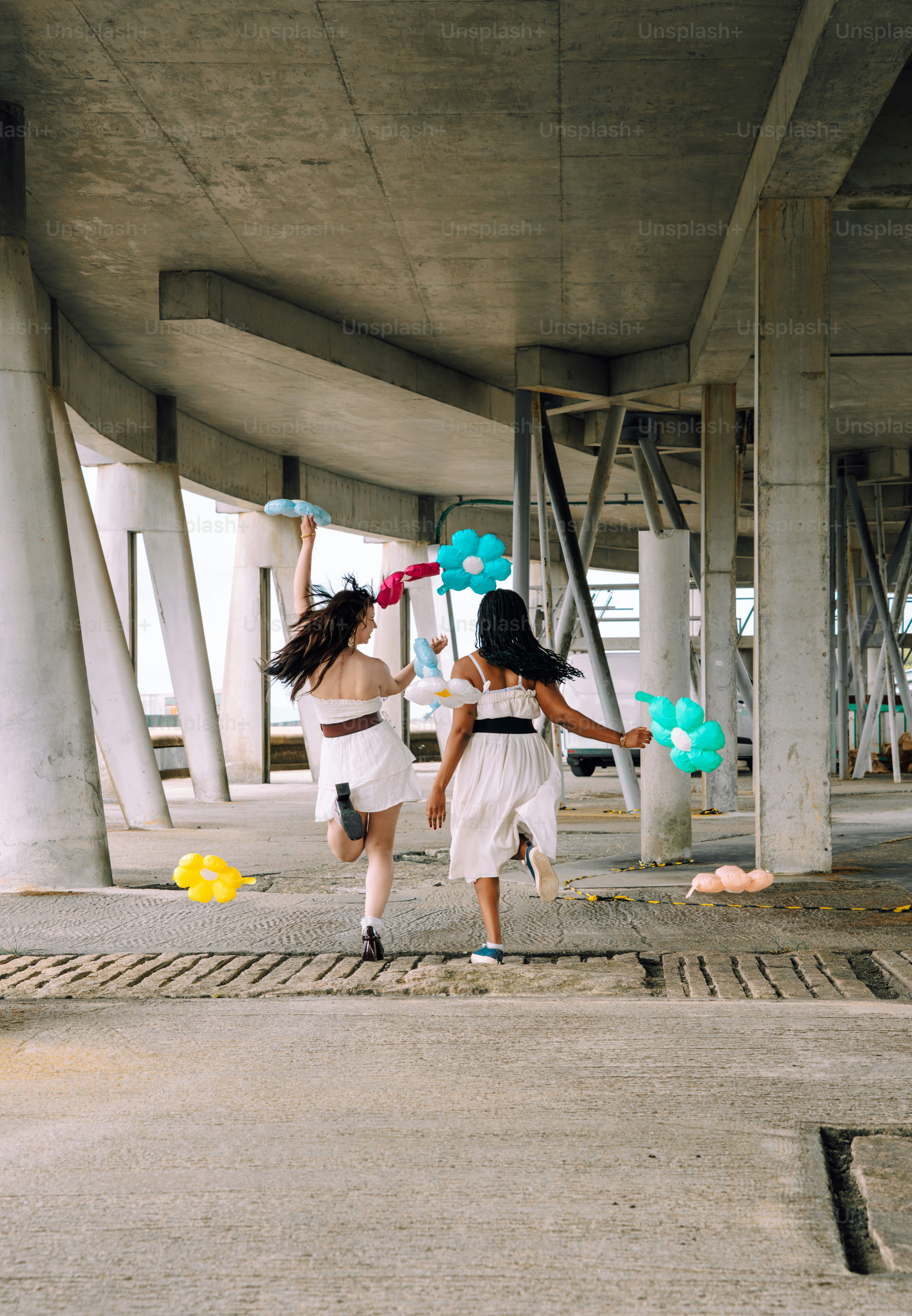 Two women run with balloons underneath a bridge. photo – Flower Image ...