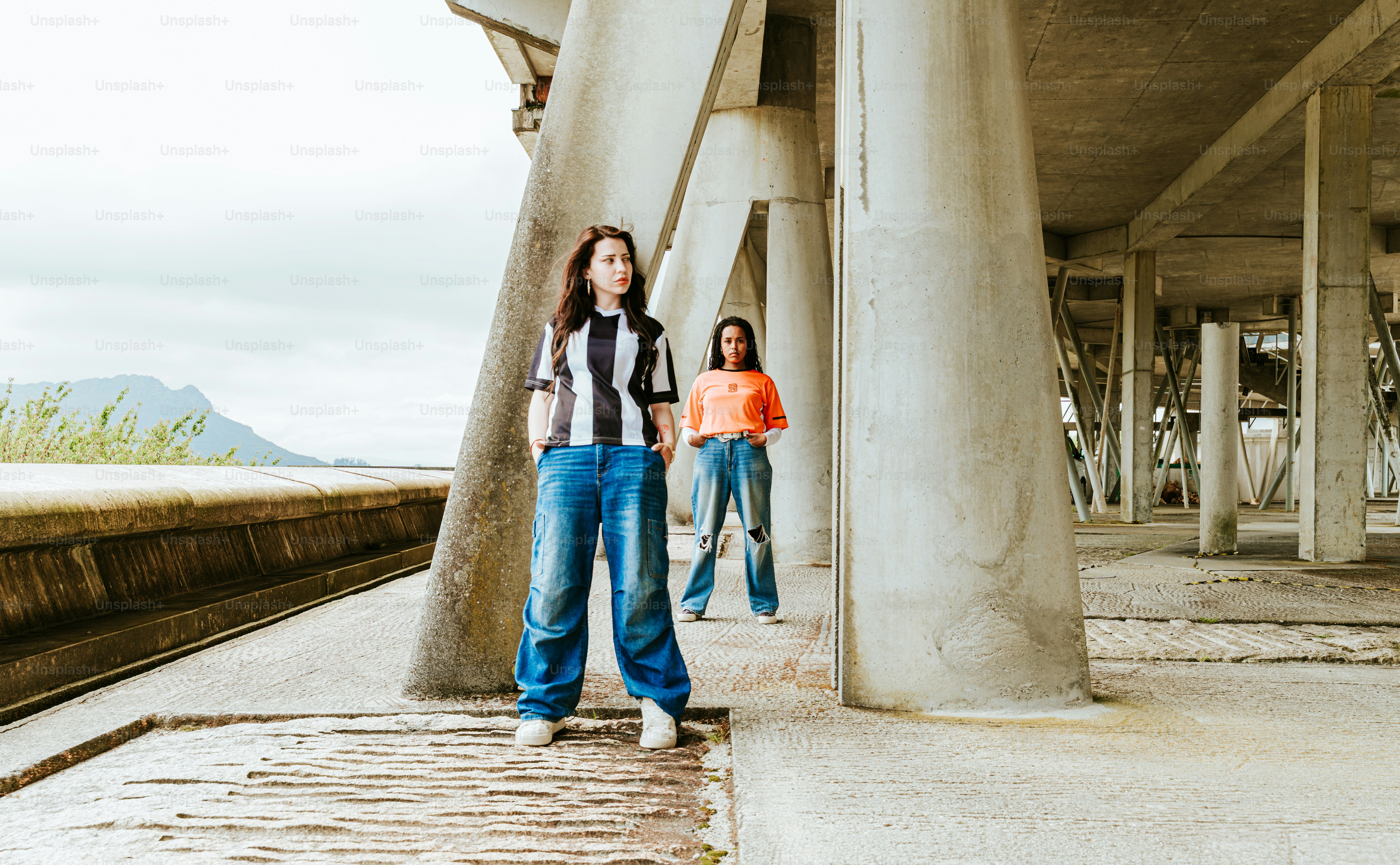 Two people are leaning over a railing. photo – Fashion Image on Unsplash