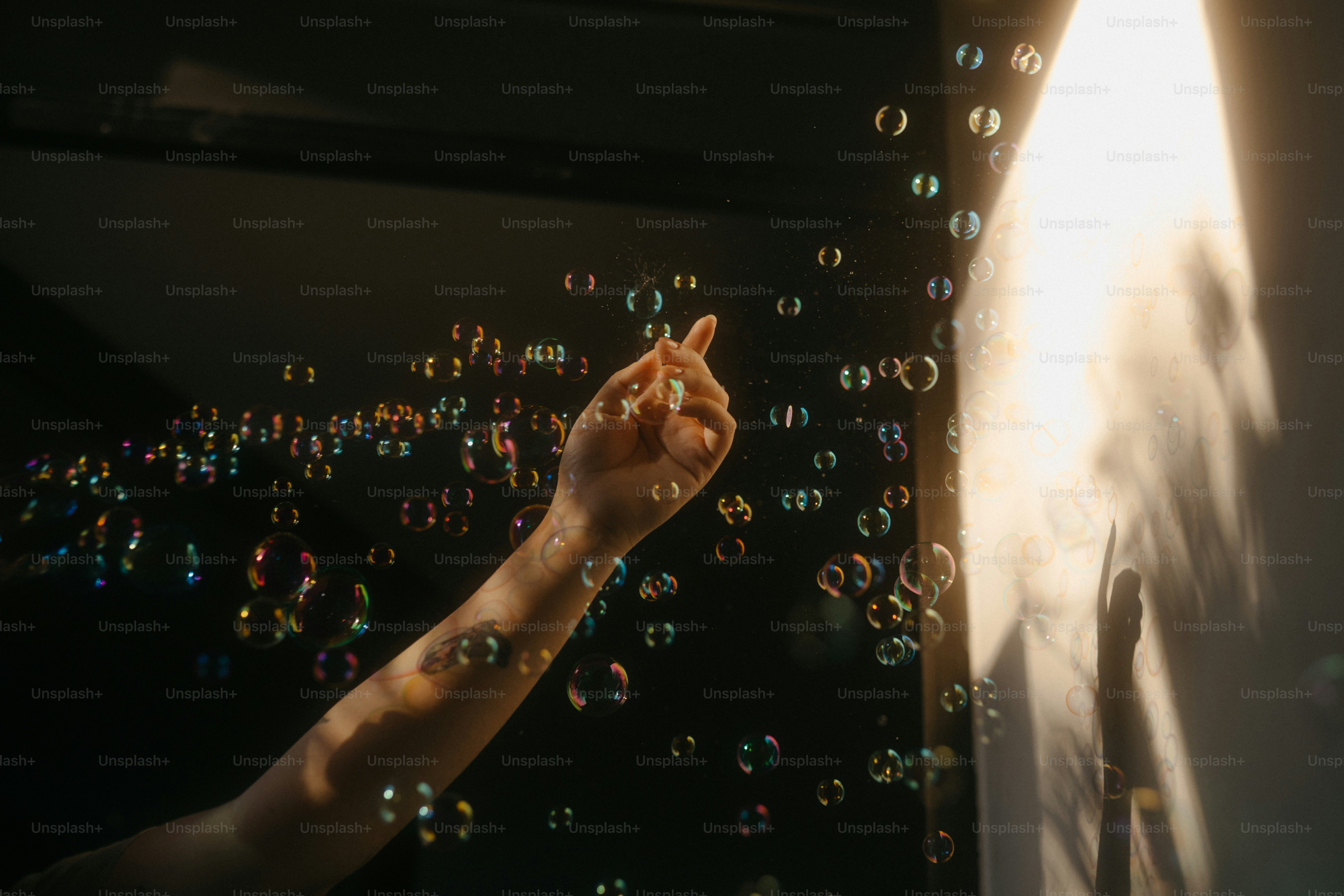 A hand touches bubbles floating in sunlight. photo – Bubbles Image on ...