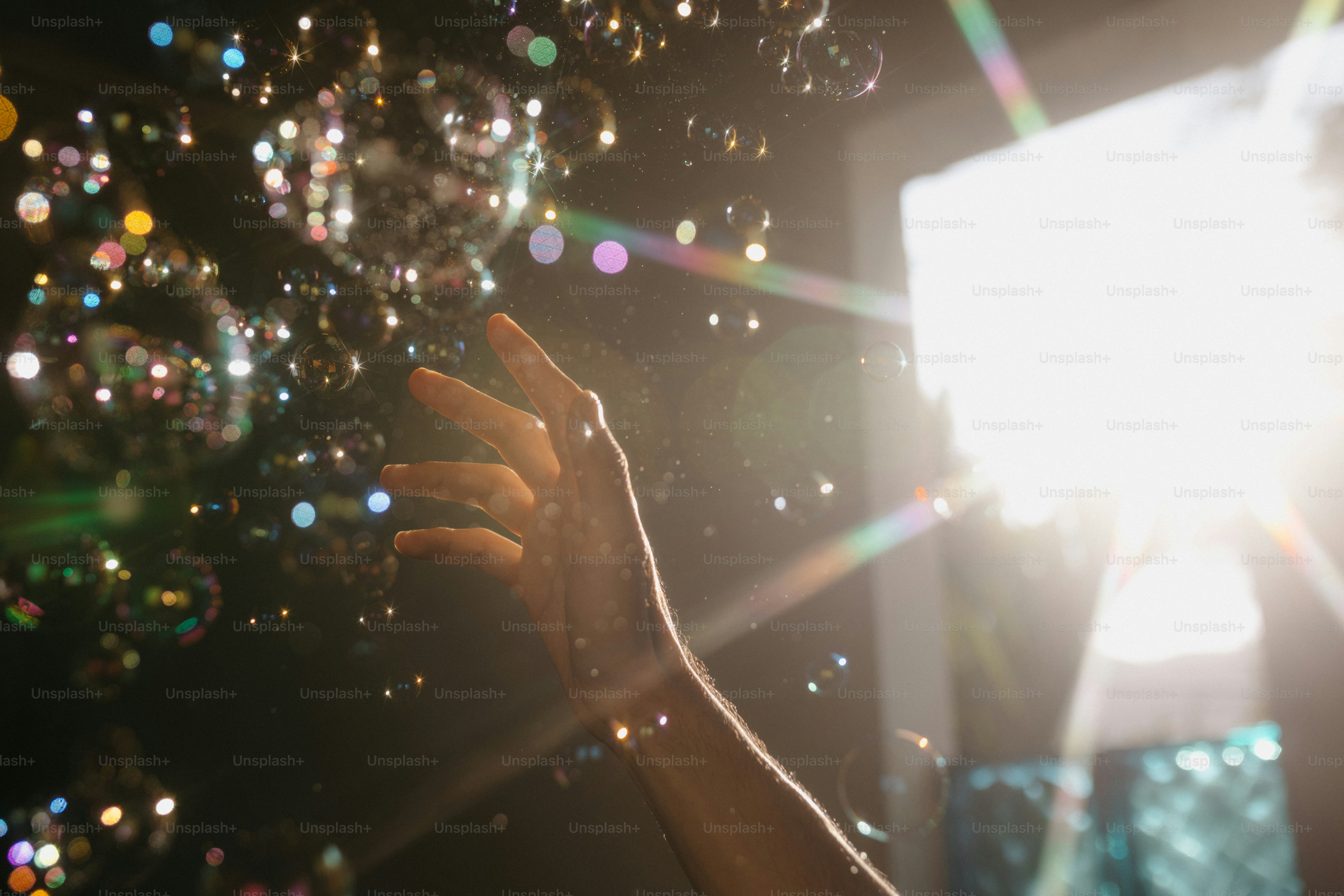 A hand reaches out to bubbles in the air. photo – Bubbles Image on Unsplash