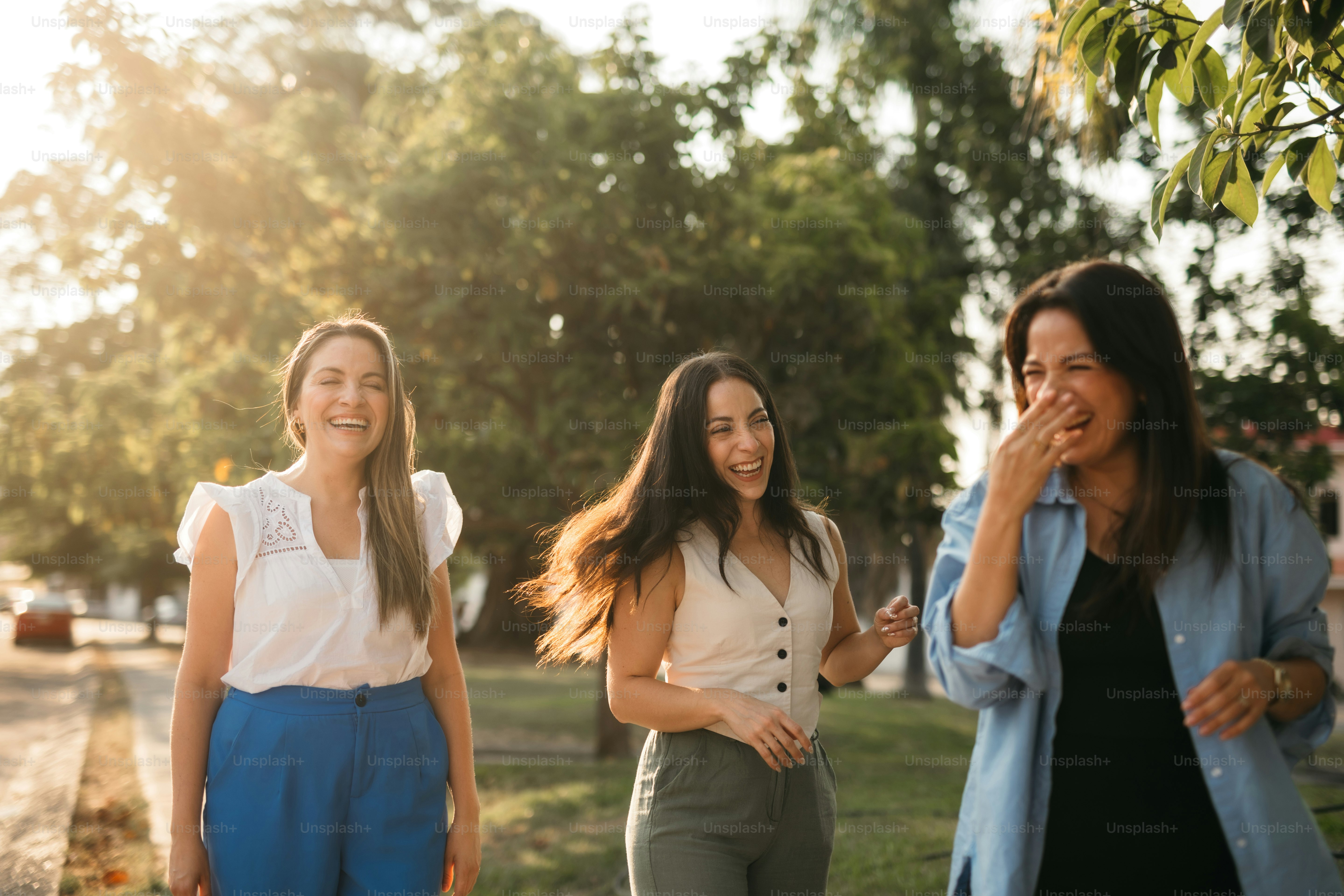 Three friends laugh together outdoors in the sunshine. photo – Portrait ...