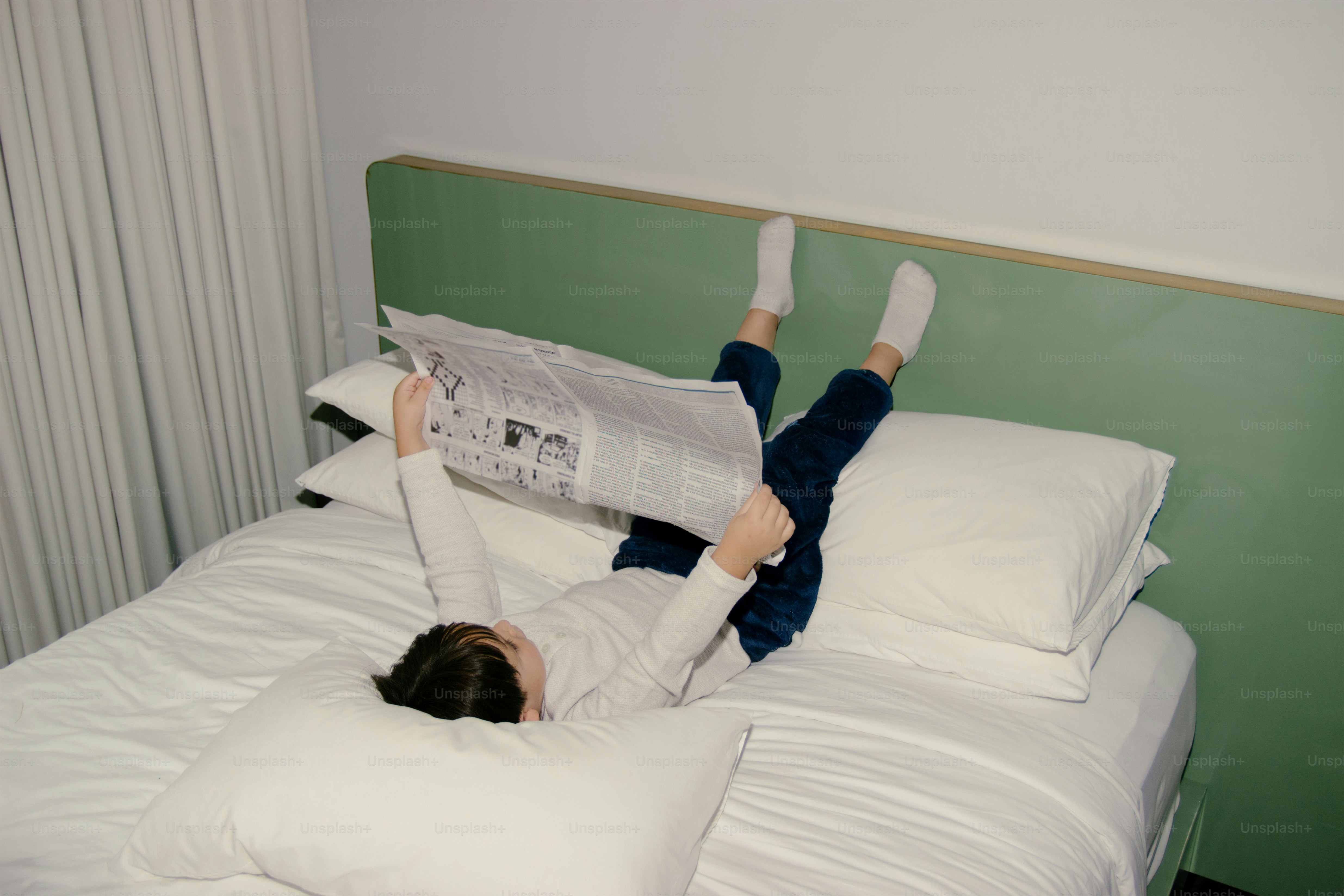 Person reads newspaper upside down on a bed. photo – Travel Image on ...