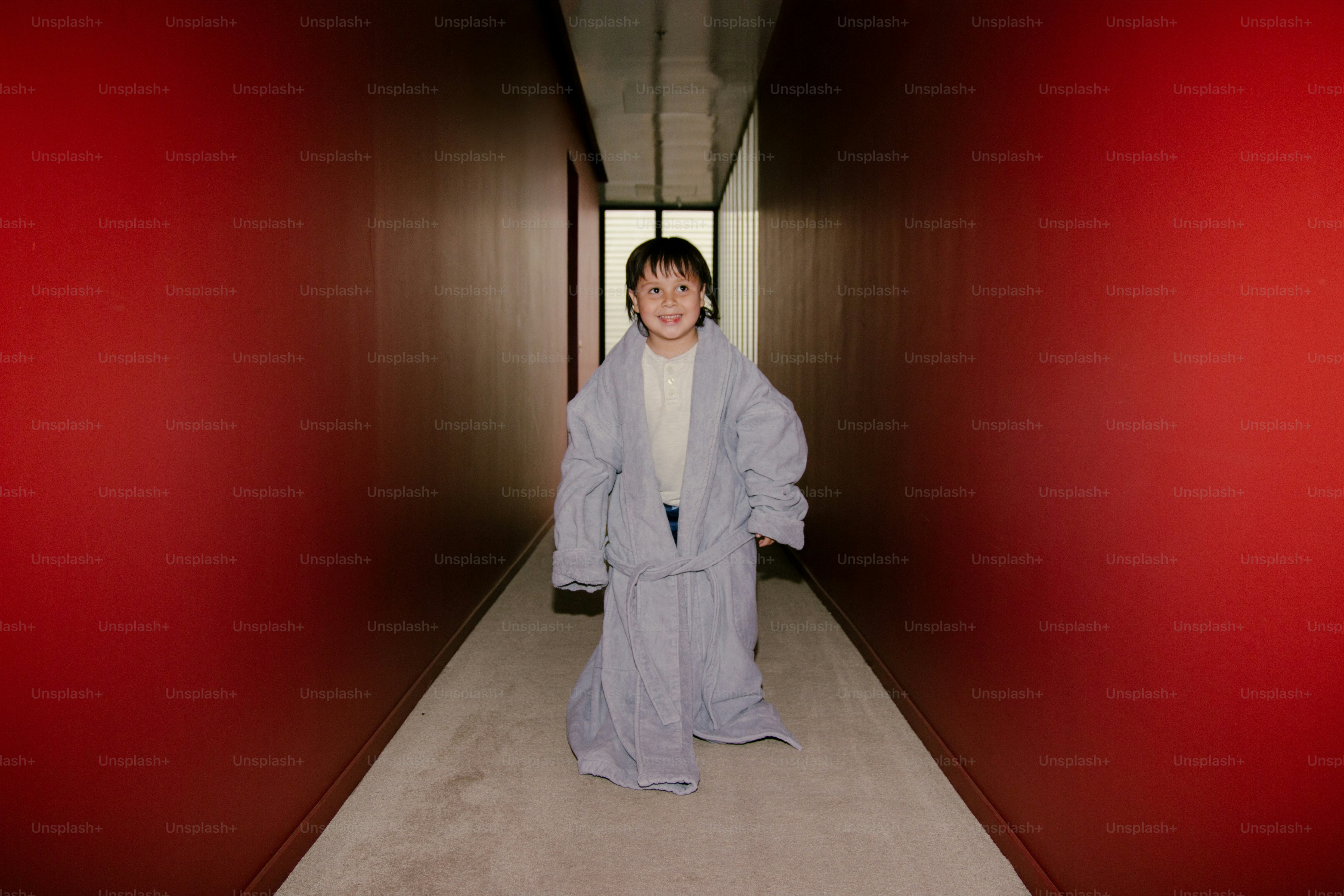 A little girl smiles down a red hallway. photo – Travel Image on Unsplash