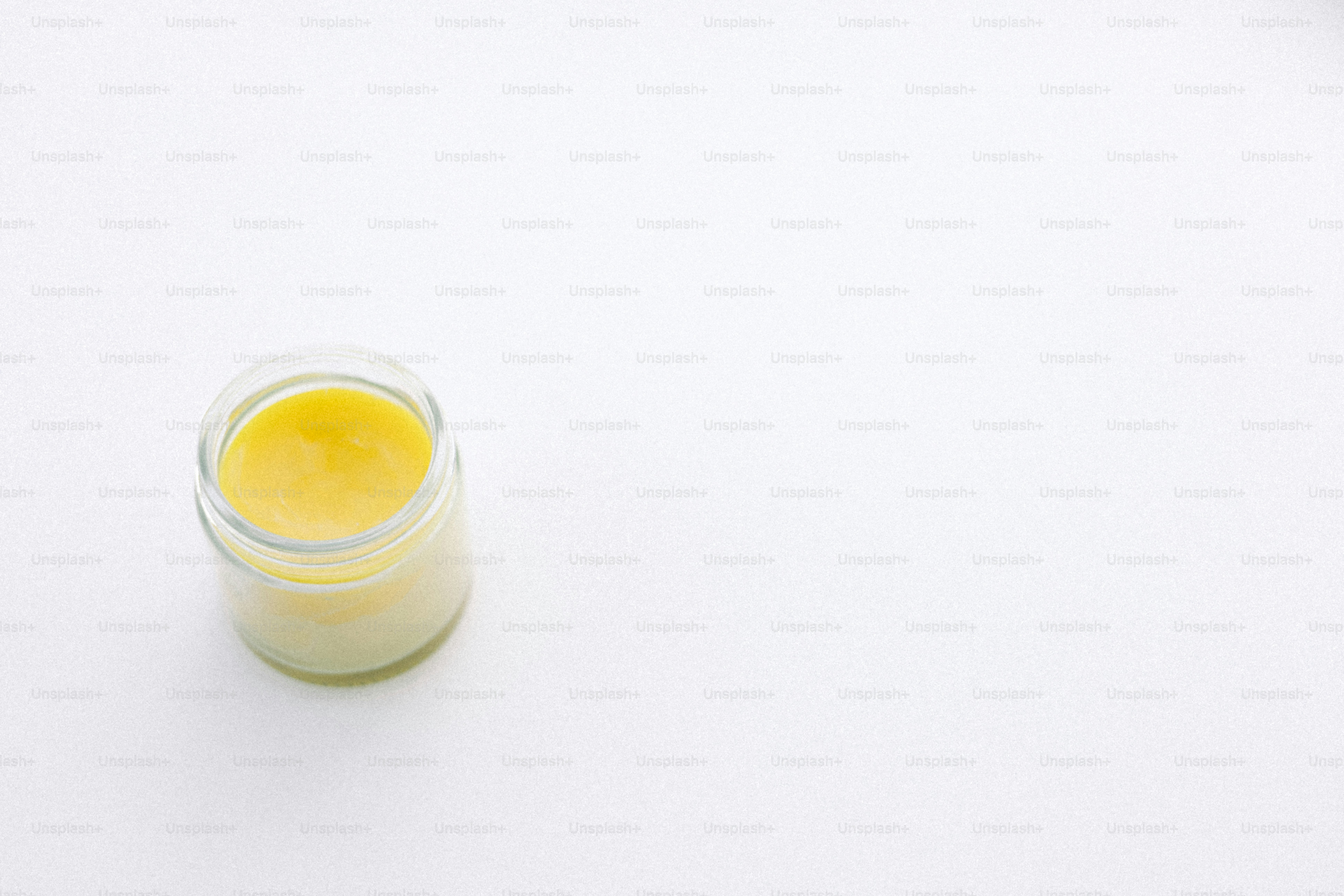 A jar contains yellow ointment on white surface. photo – Minimal Image ...