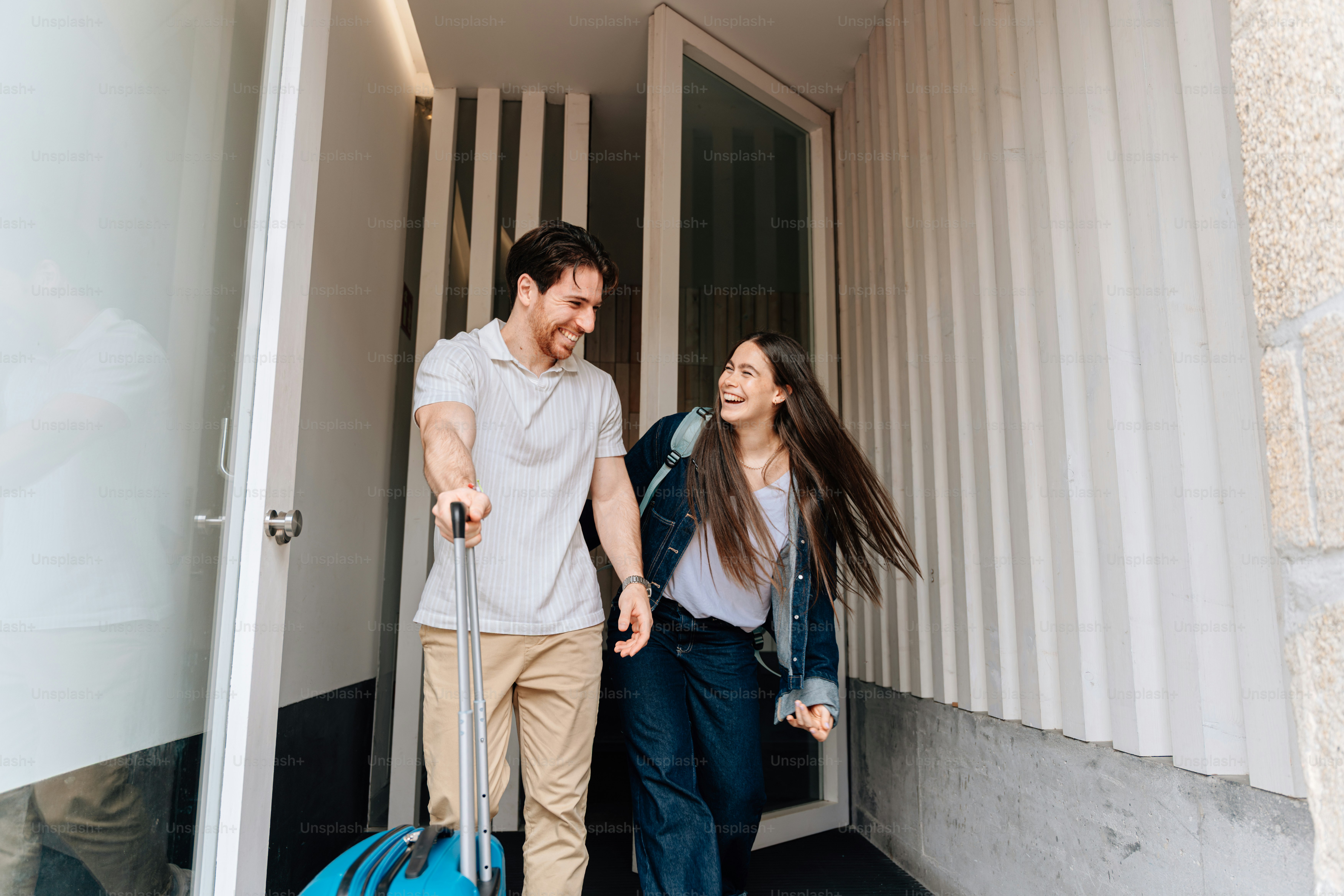 Couple exits a building with luggage, ready for travel. photo – Travel ...
