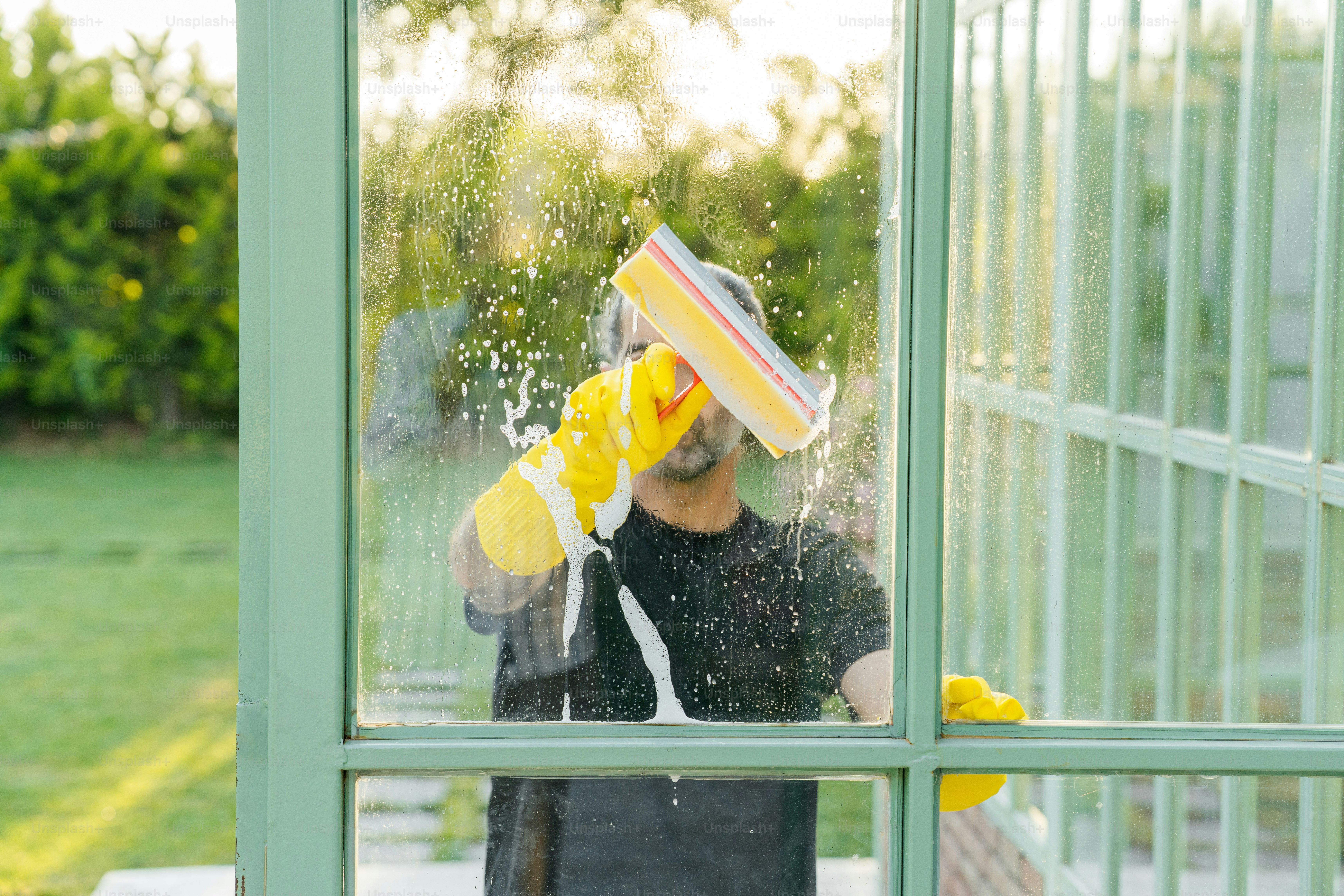 Man wearing gloves cleans a window with a squeegee. photo – Spring ...