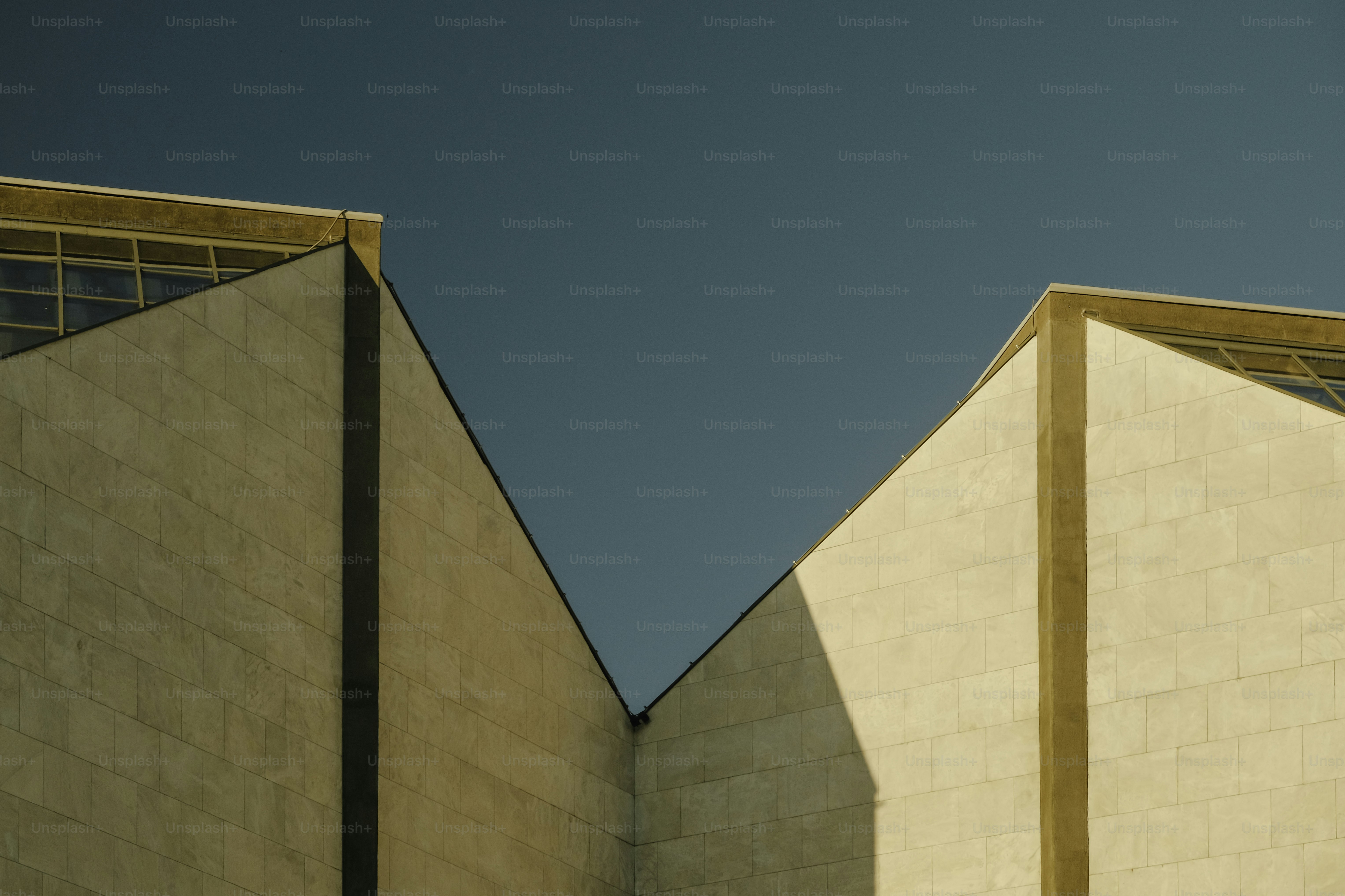 Two buildings with angular rooftops against blue sky. photo ...