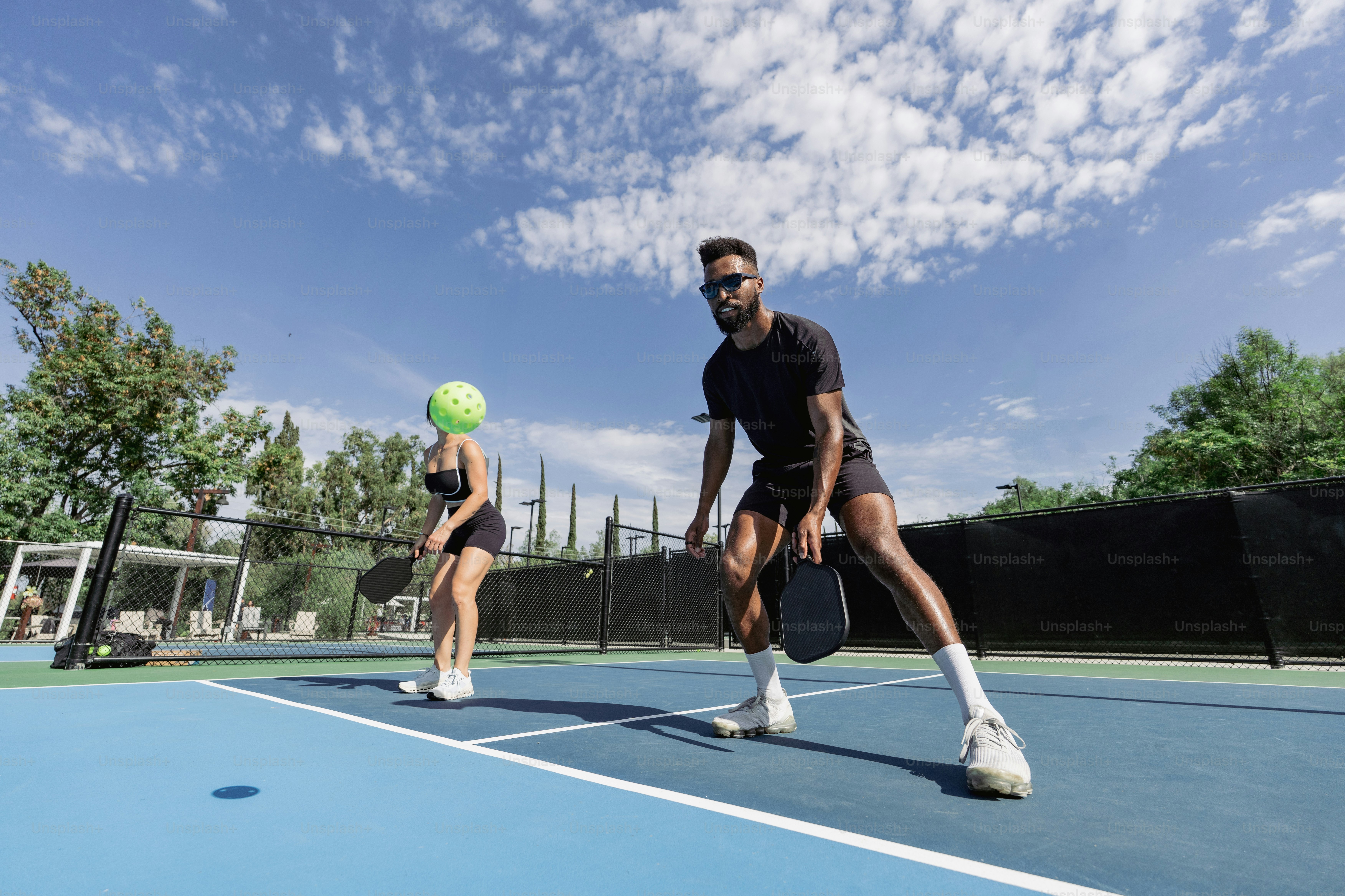 Two people play pickleball on a sunny court. photo – Sports Image on ...