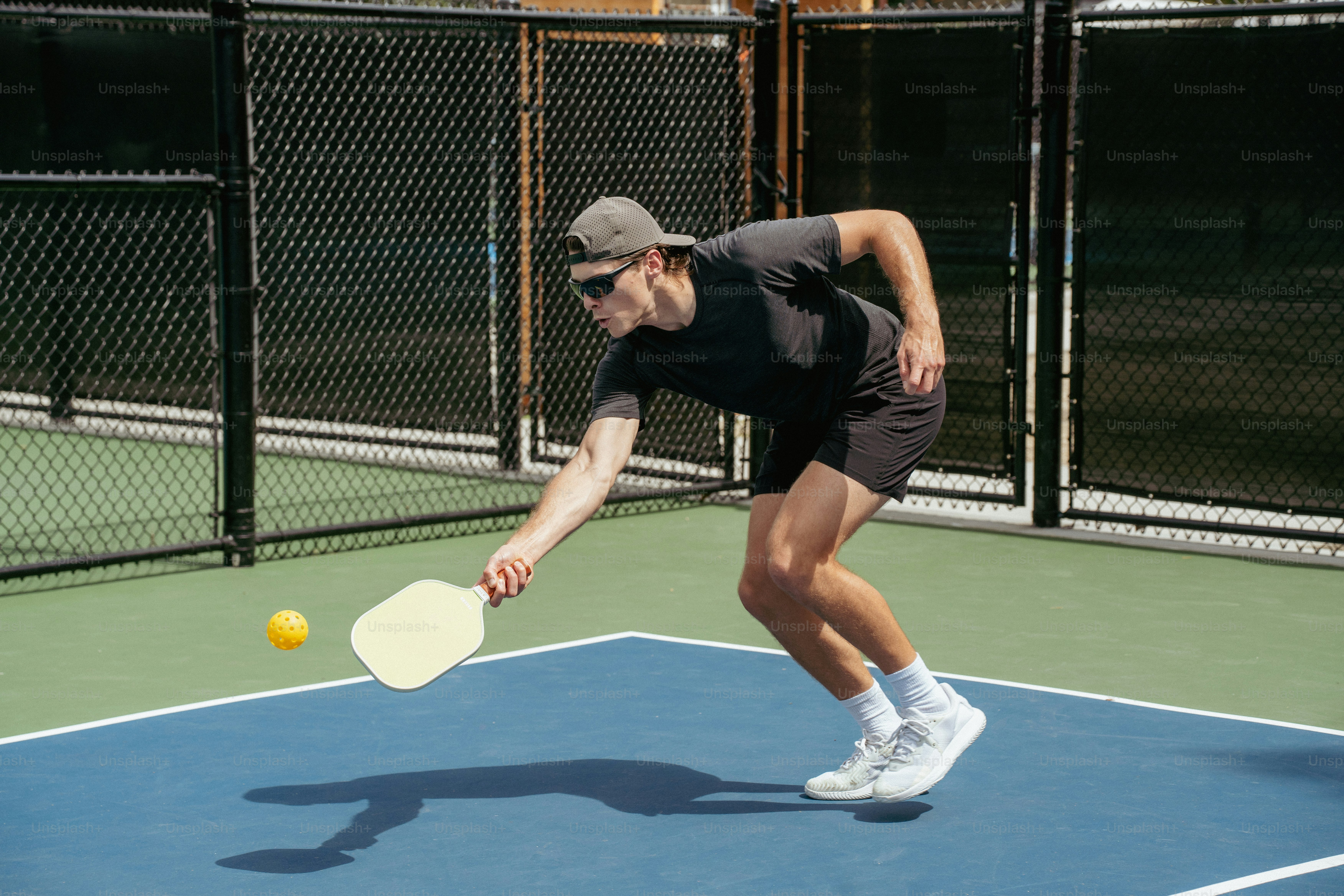 Man plays pickleball, reaching for the ball. photo – Sports Image on ...