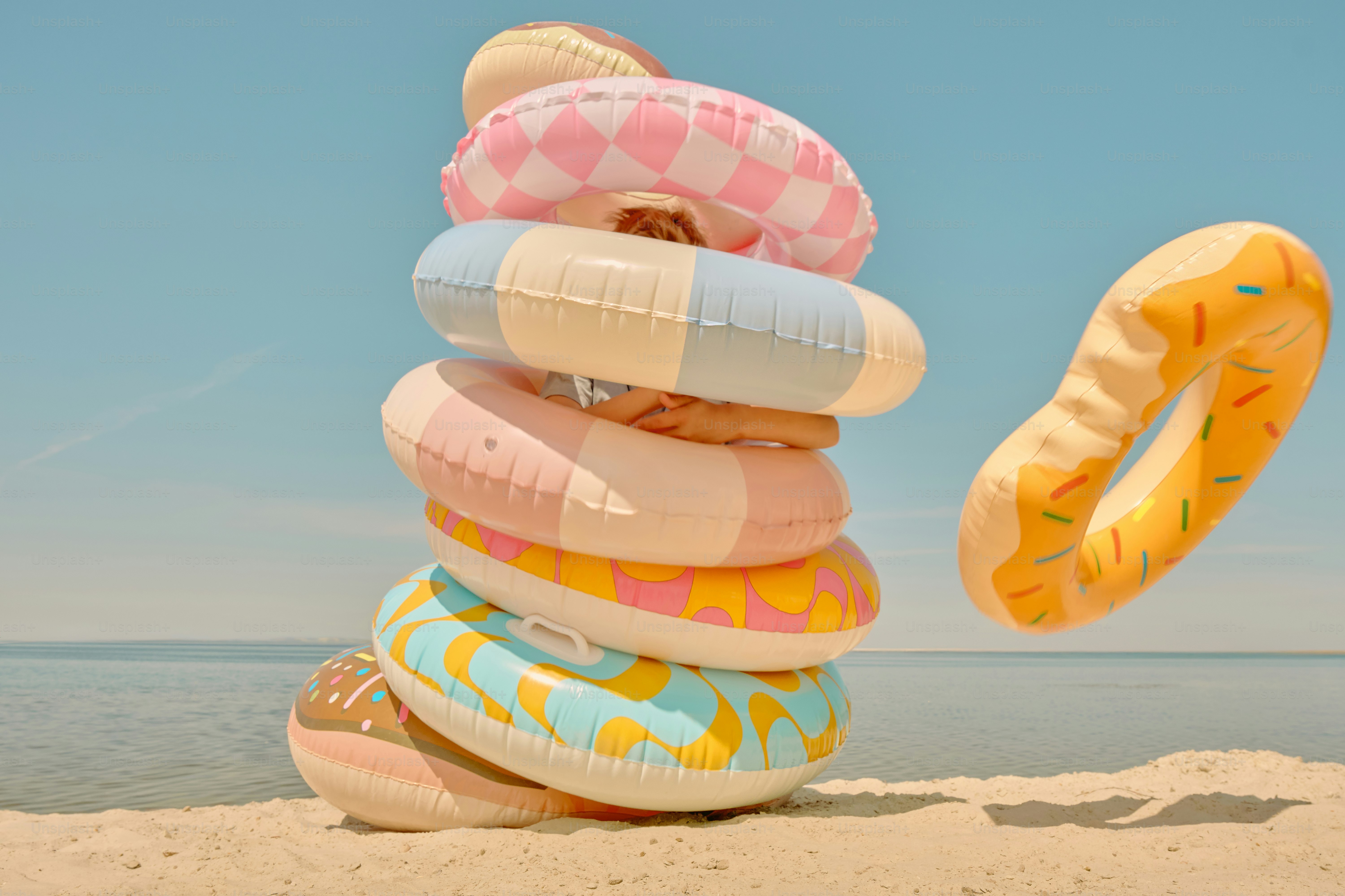 Pool floats are stacked on a sandy beach. photo – Beach Image on Unsplash