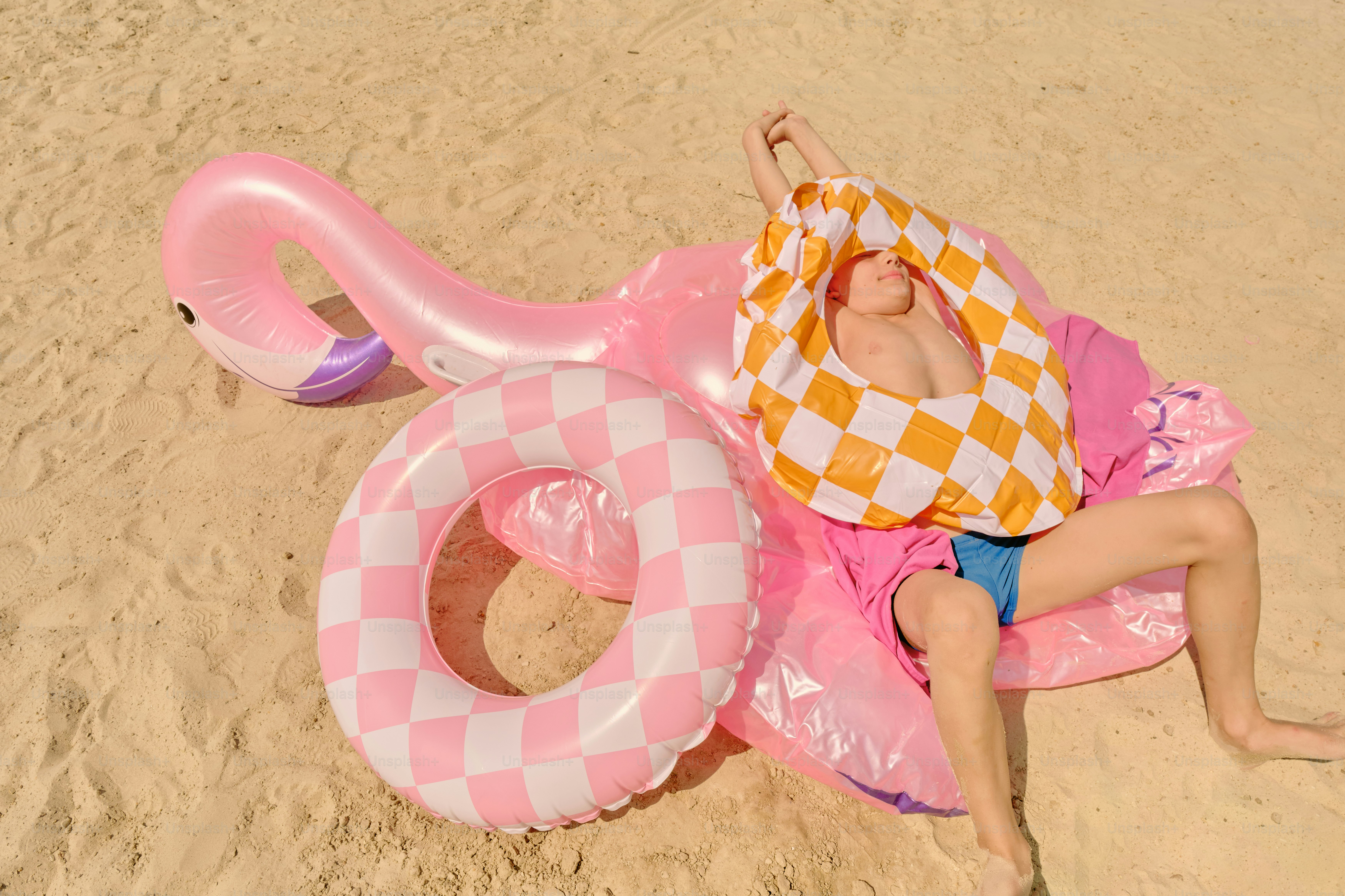 Person relaxes on flamingo floaty at the beach. photo – Beach Image on ...