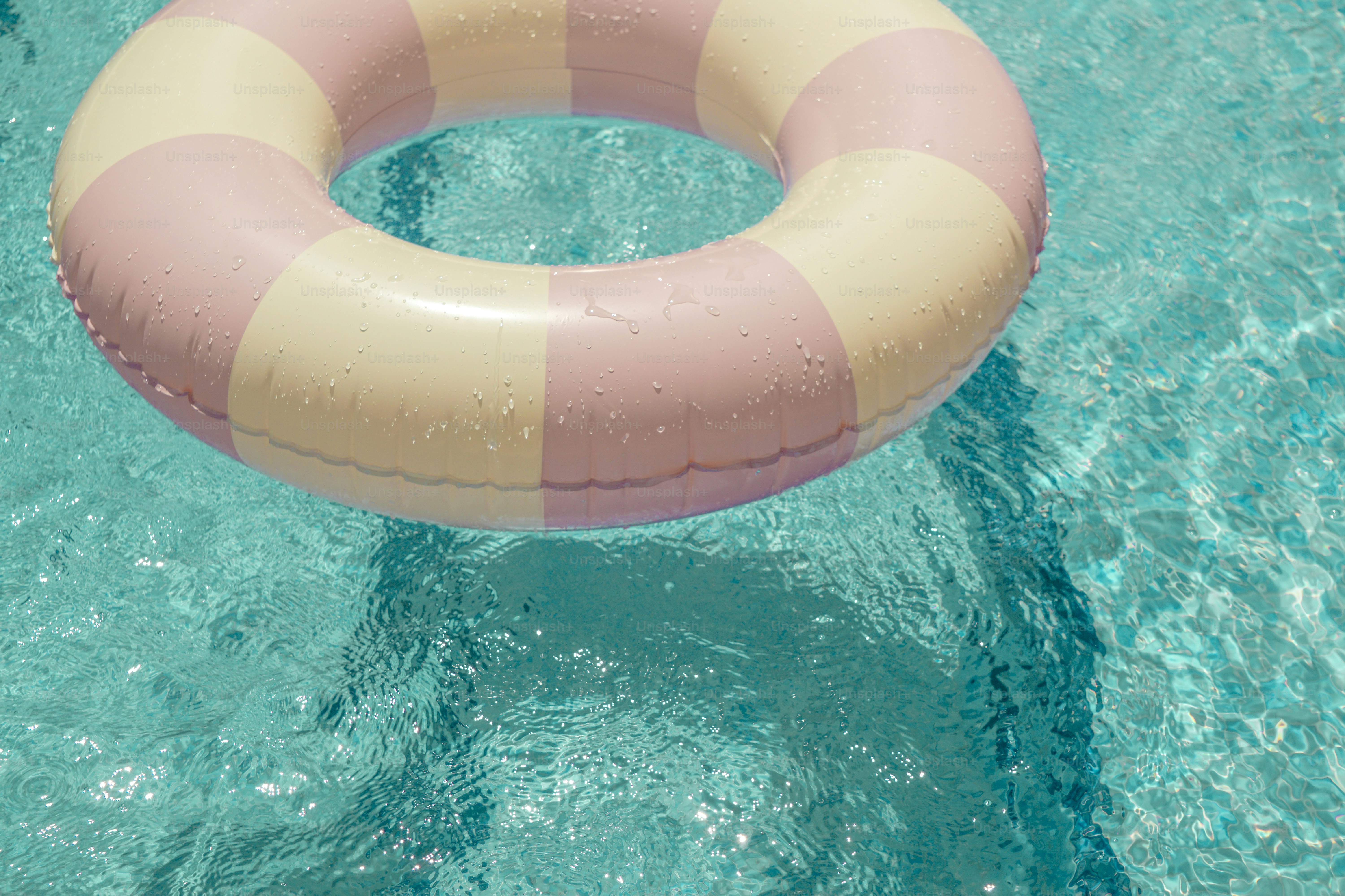 A pink and white inflatable ring floats in water. photo – Summer Image ...