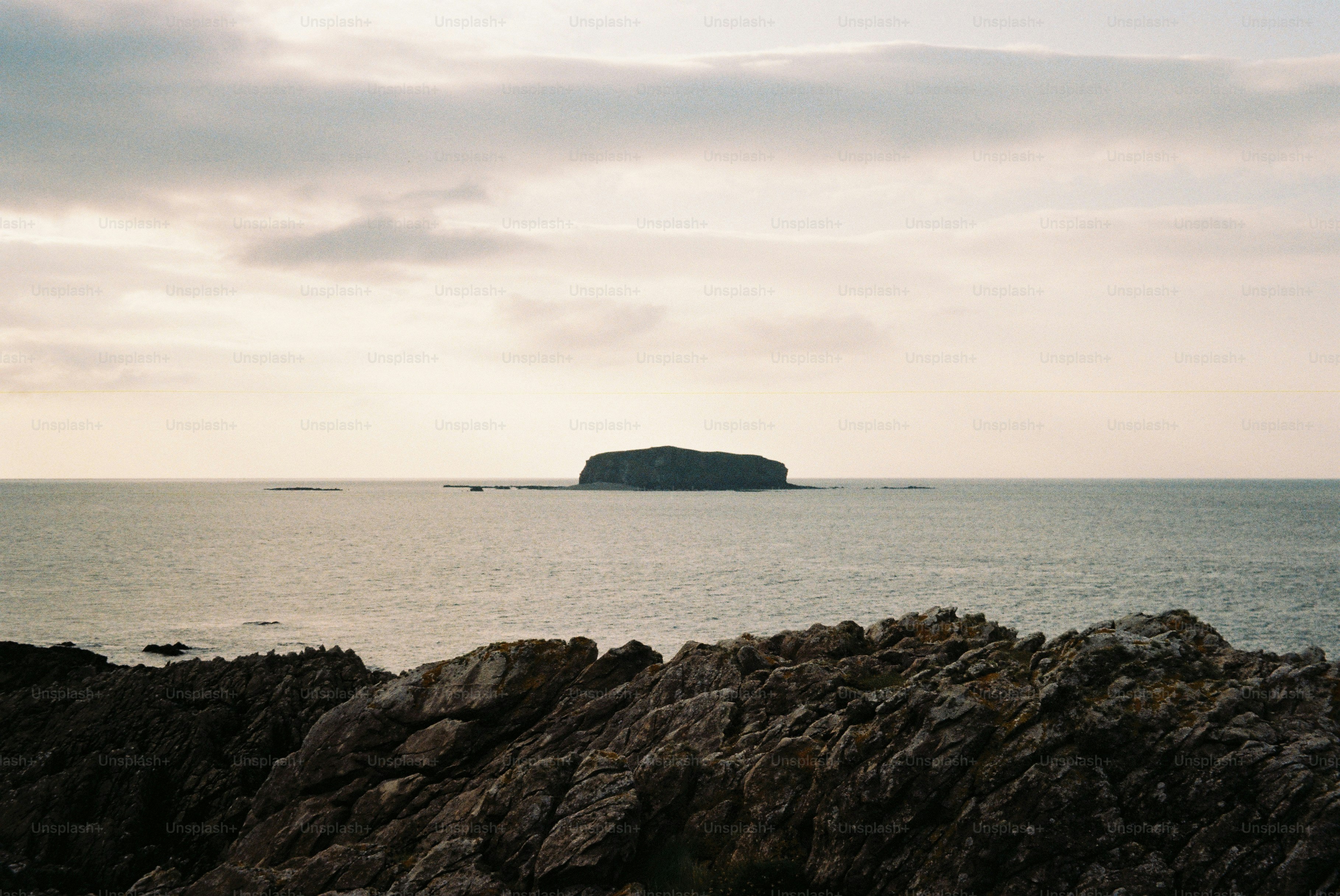A rocky foreground leads to a distant island. photo – Film photography ...