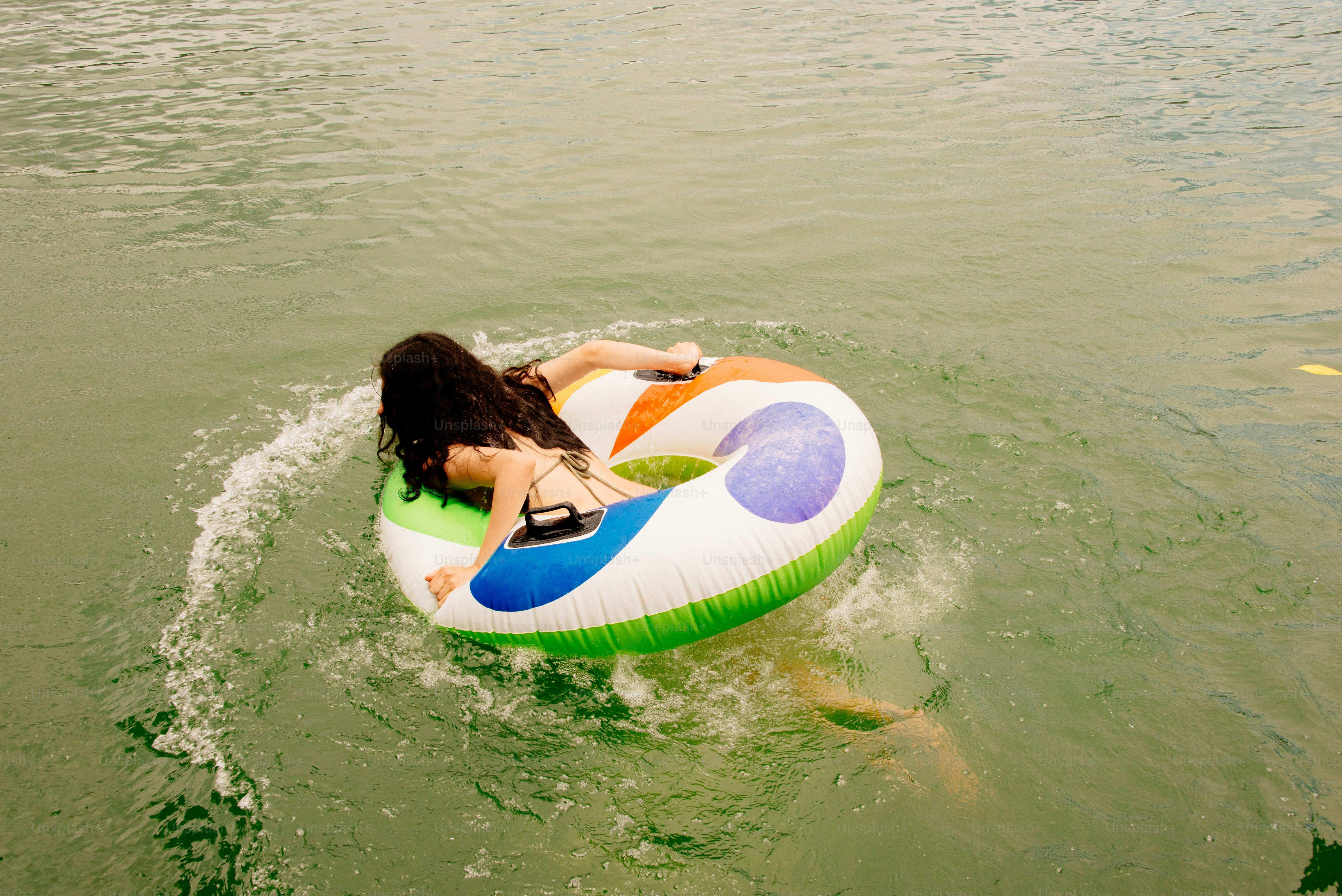 A woman floats on an inner tube in water. photo – Summer fun Image on ...