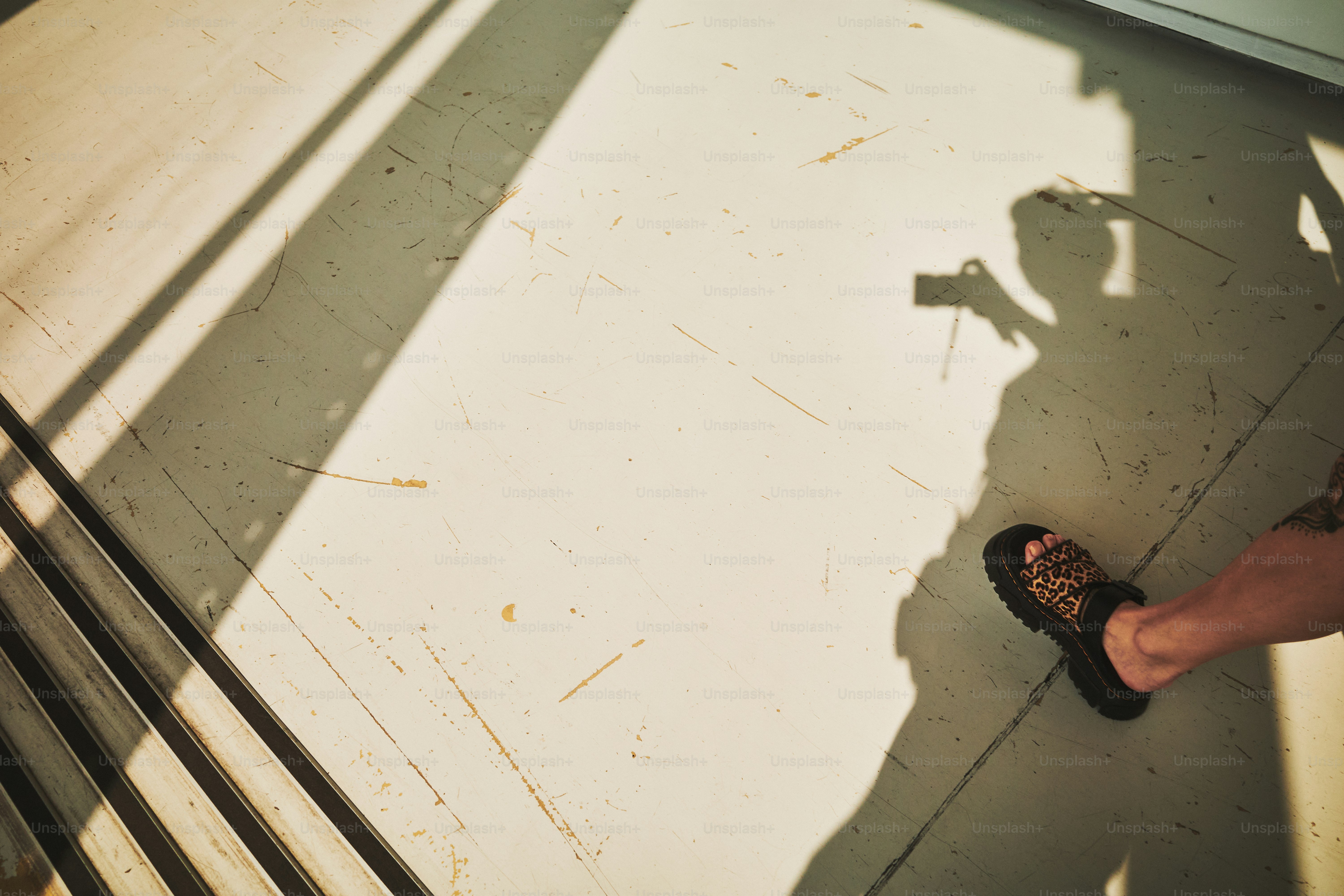 A person's shadow on a sunlit floor. photo – Abstract Image on Unsplash